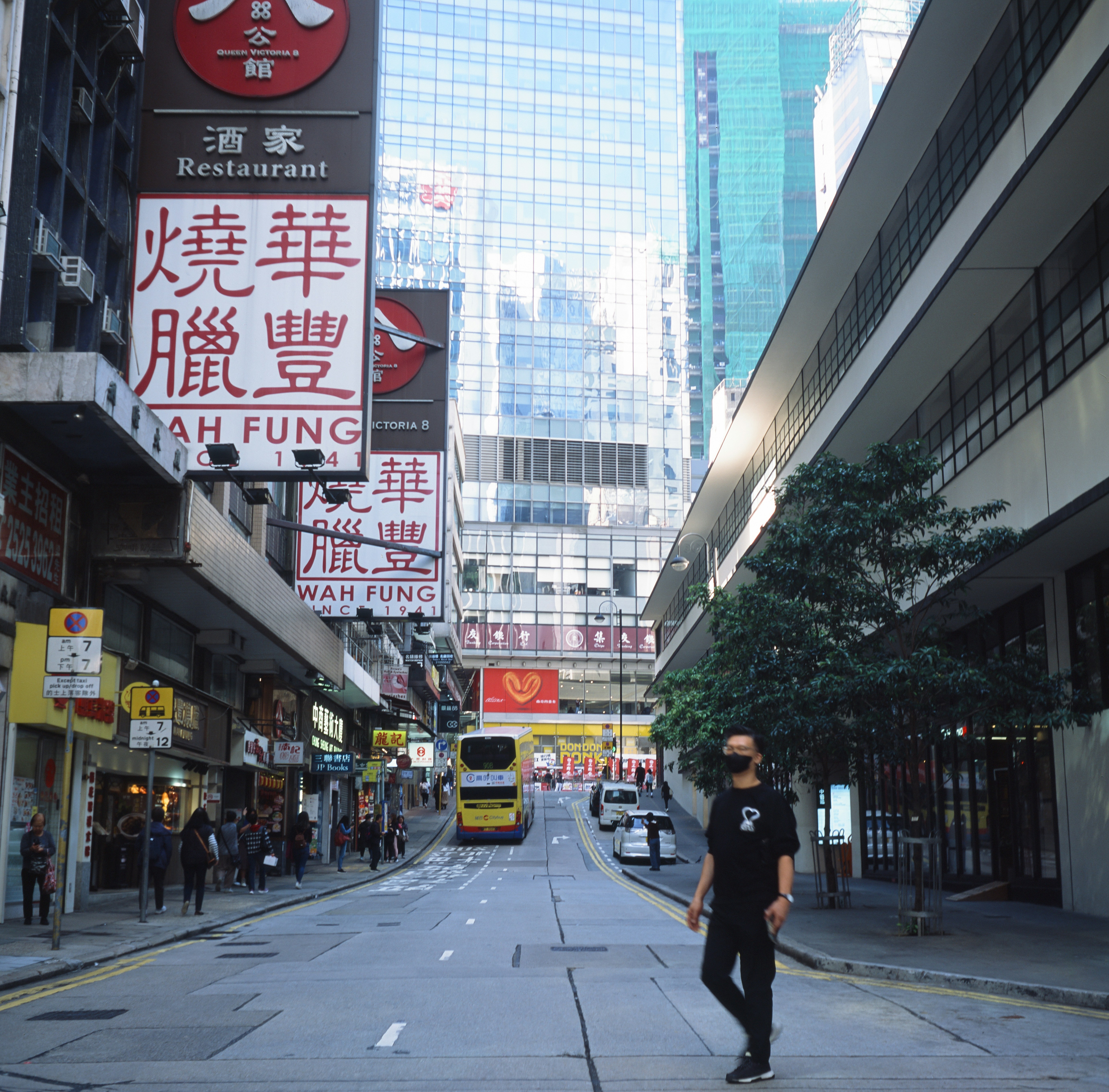 Man crossing street in hong kong with signs.