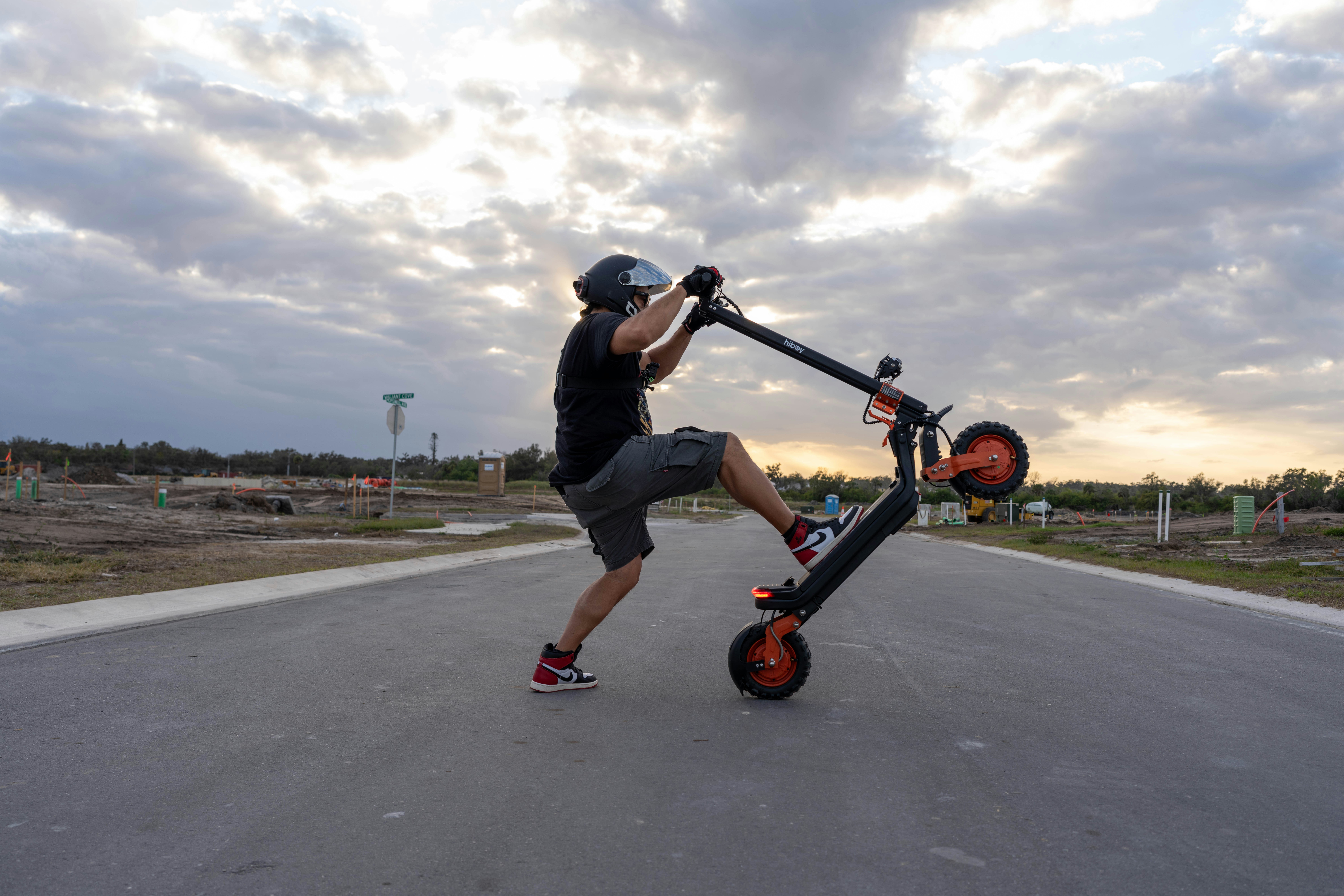 Urban rider mid-wheelie on a smooth road at sunset