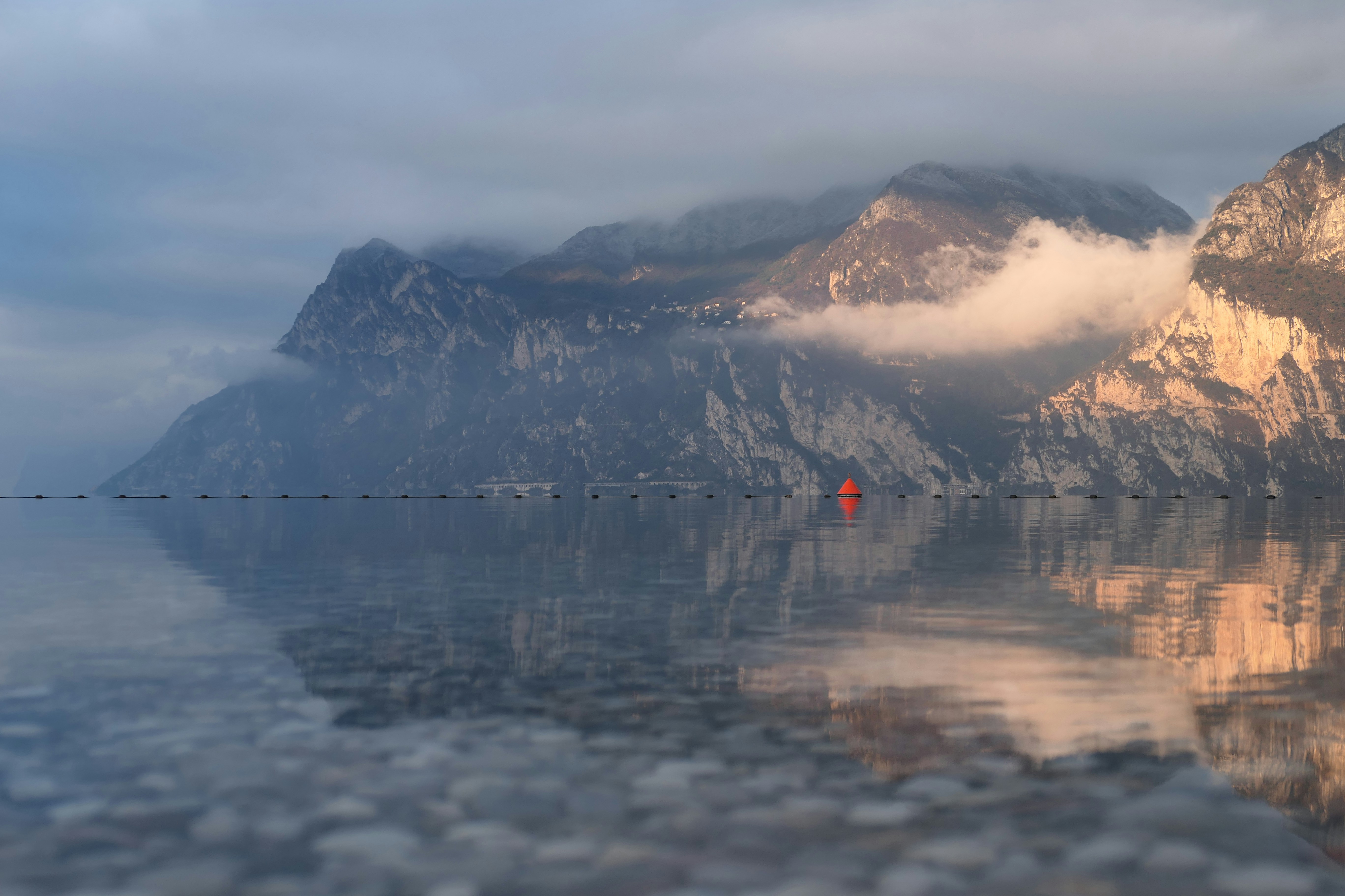 Mist-Bound Peaks and a Red Beacon on Glassy Fjord