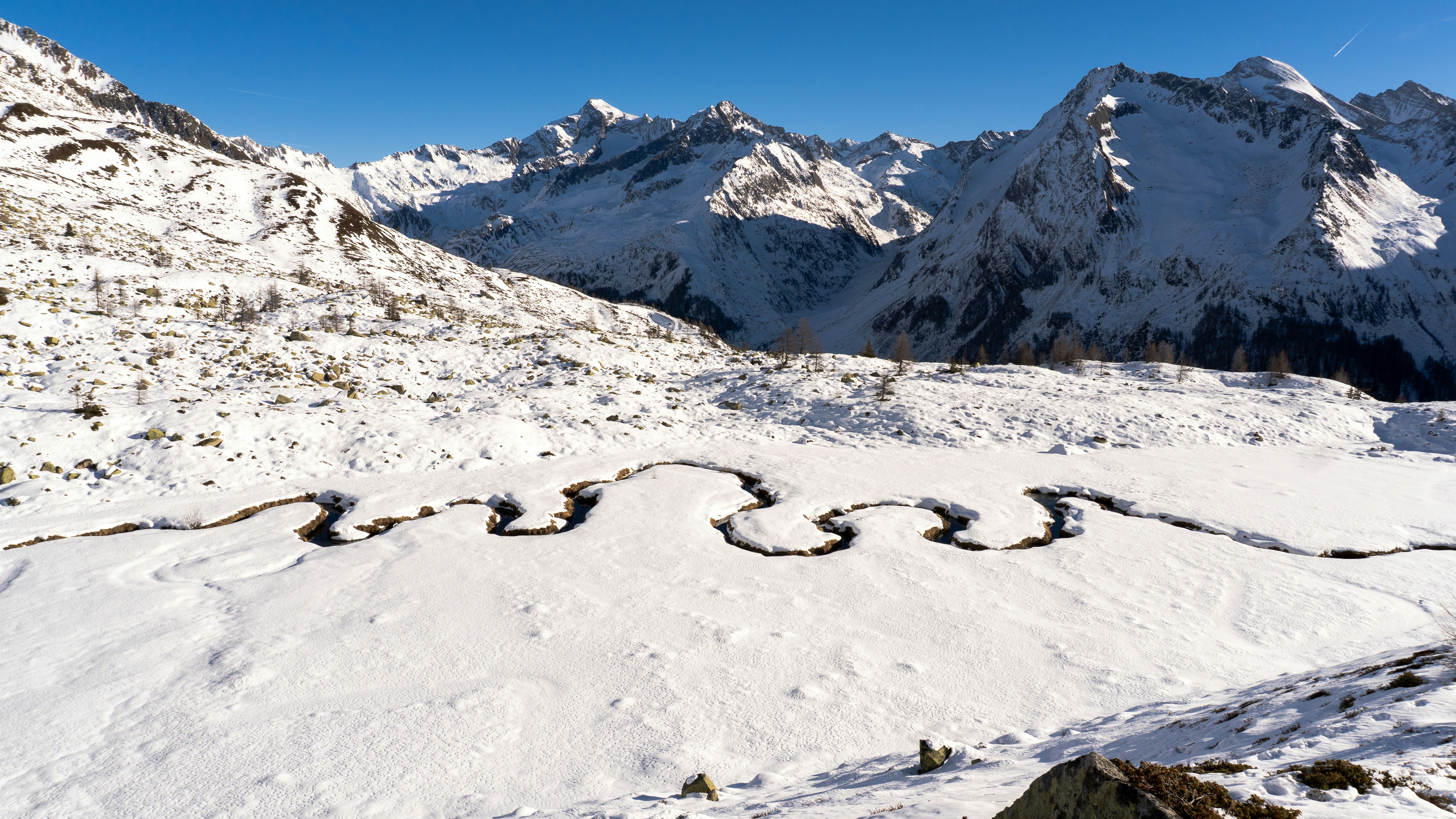Curved tracks in pristine alpine snow beneath jagged peaks