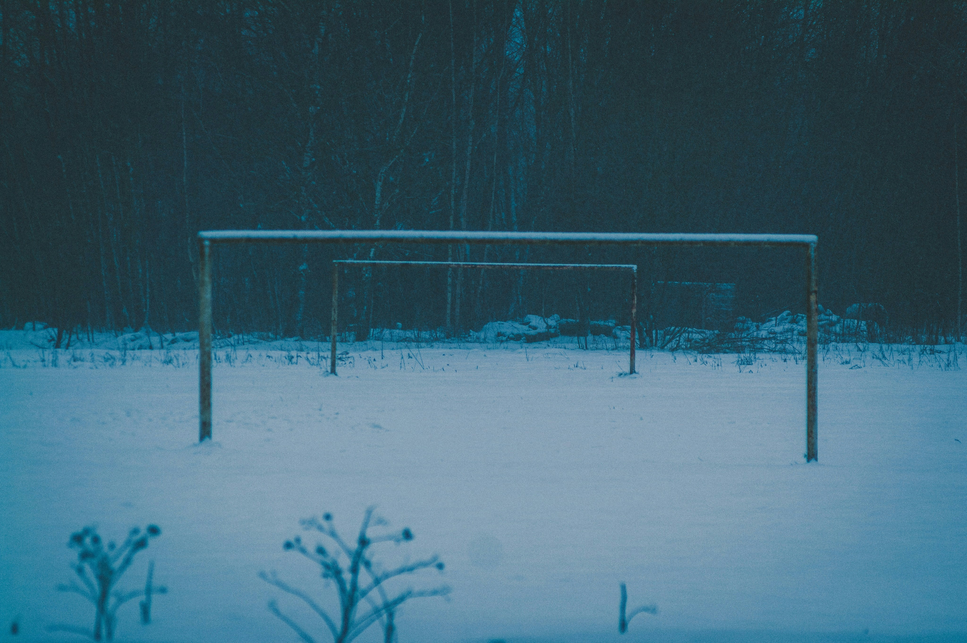 Snow-covered field with empty goalposts in winter