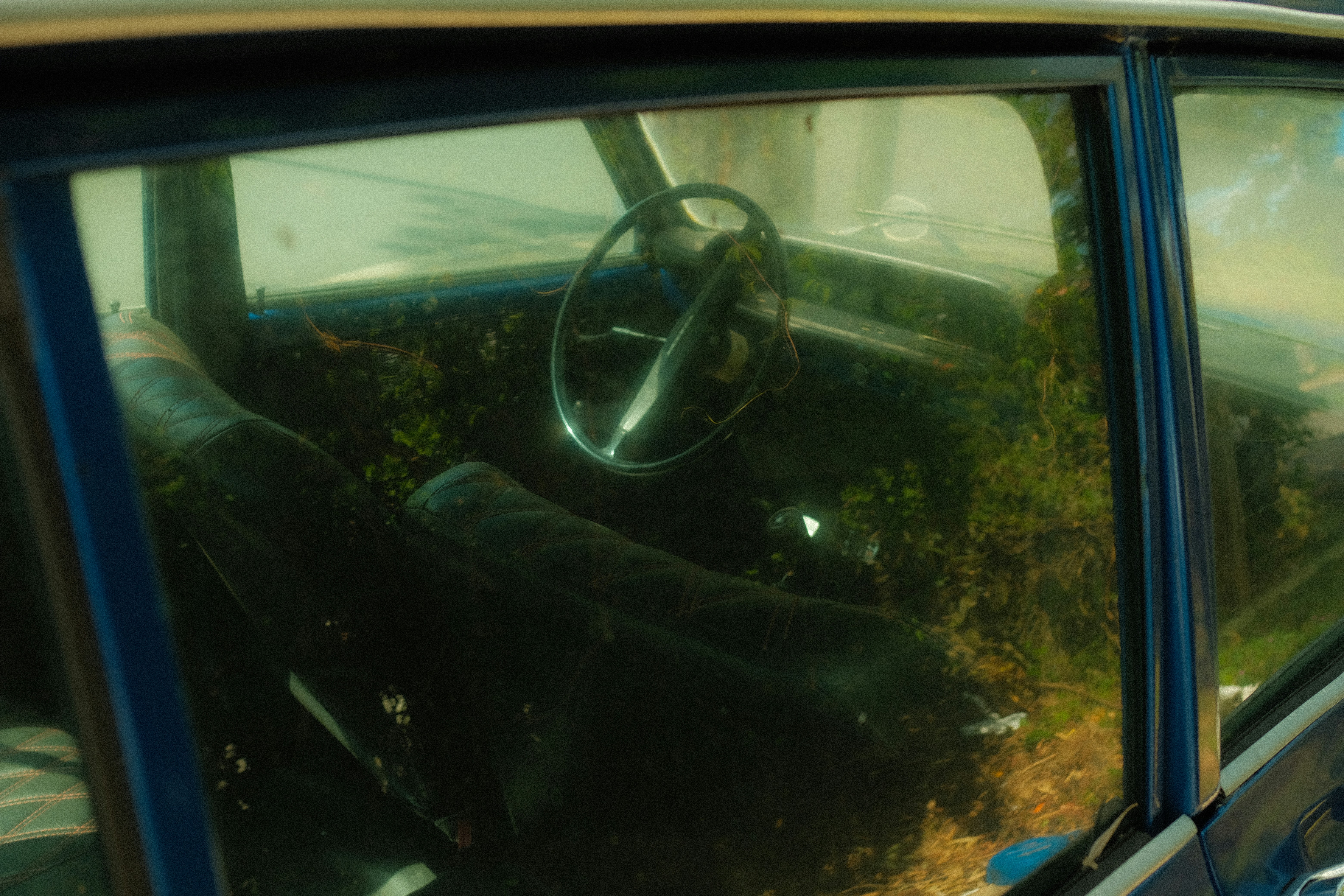 Abandoned Blue Car Window: Dusty Interior Through Glass