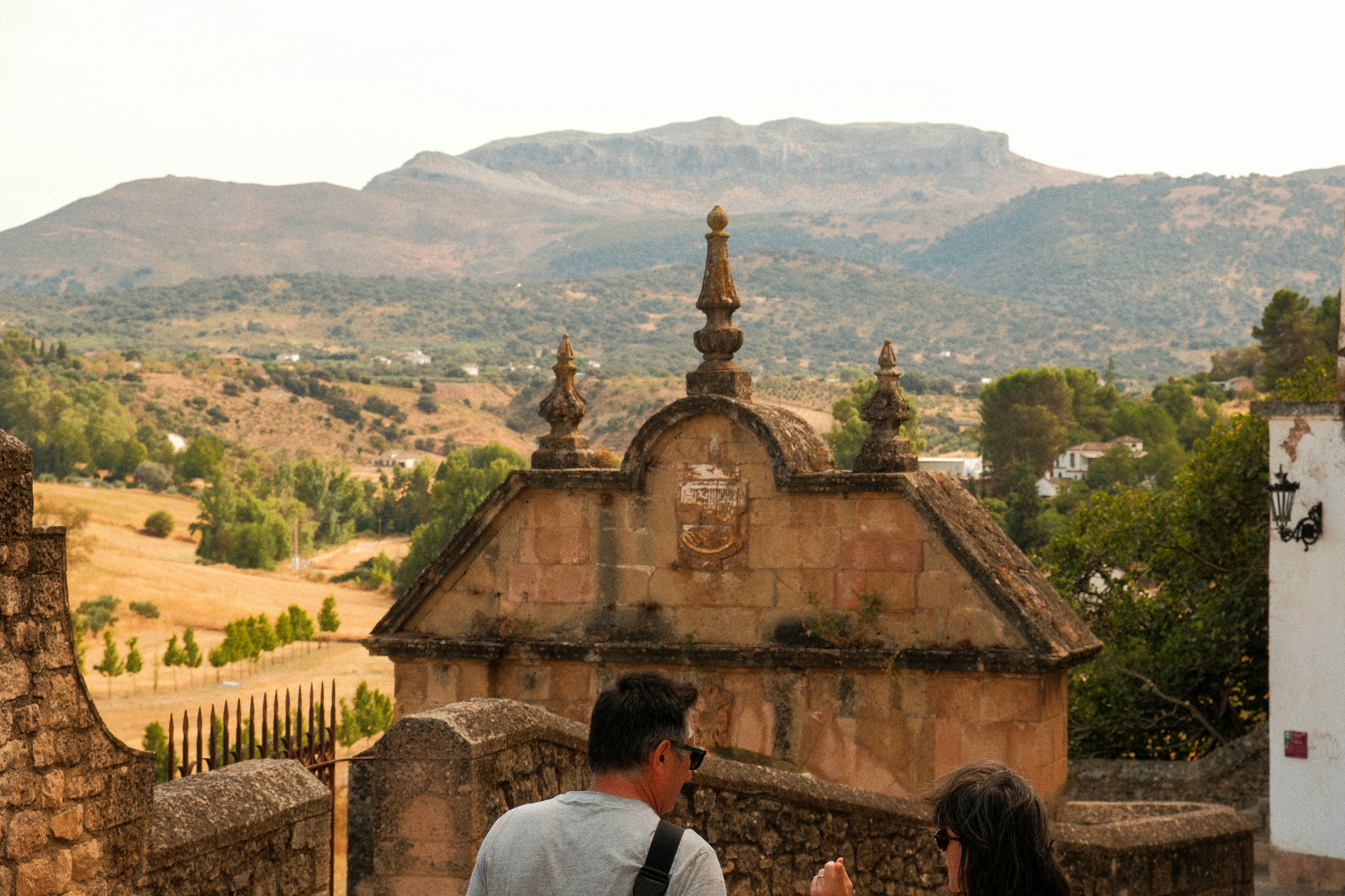 Terracotta Archway Overlook: People at the Gate with Mountain Backdrop