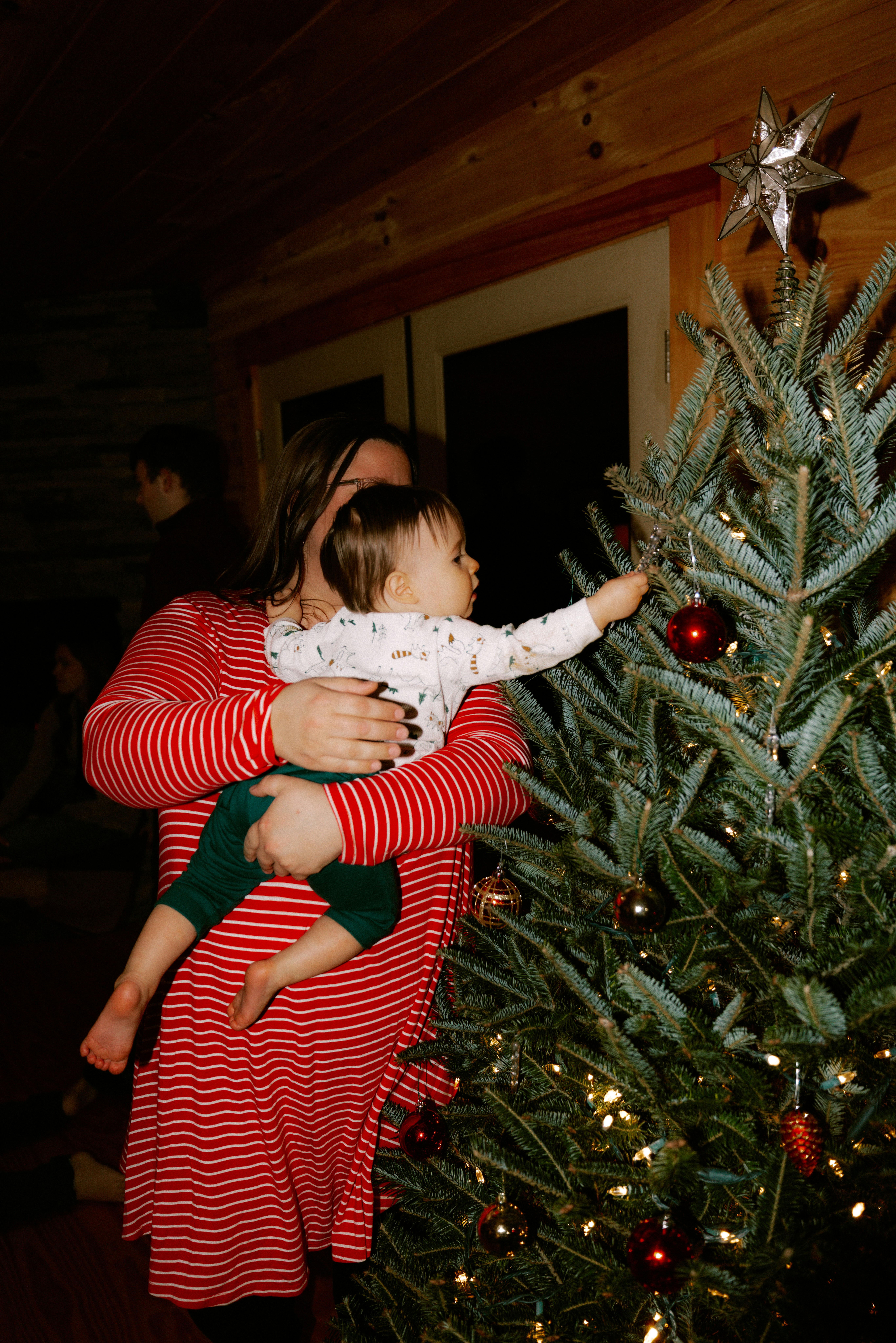 Mother and child reach toward a twinkling Christmas tree