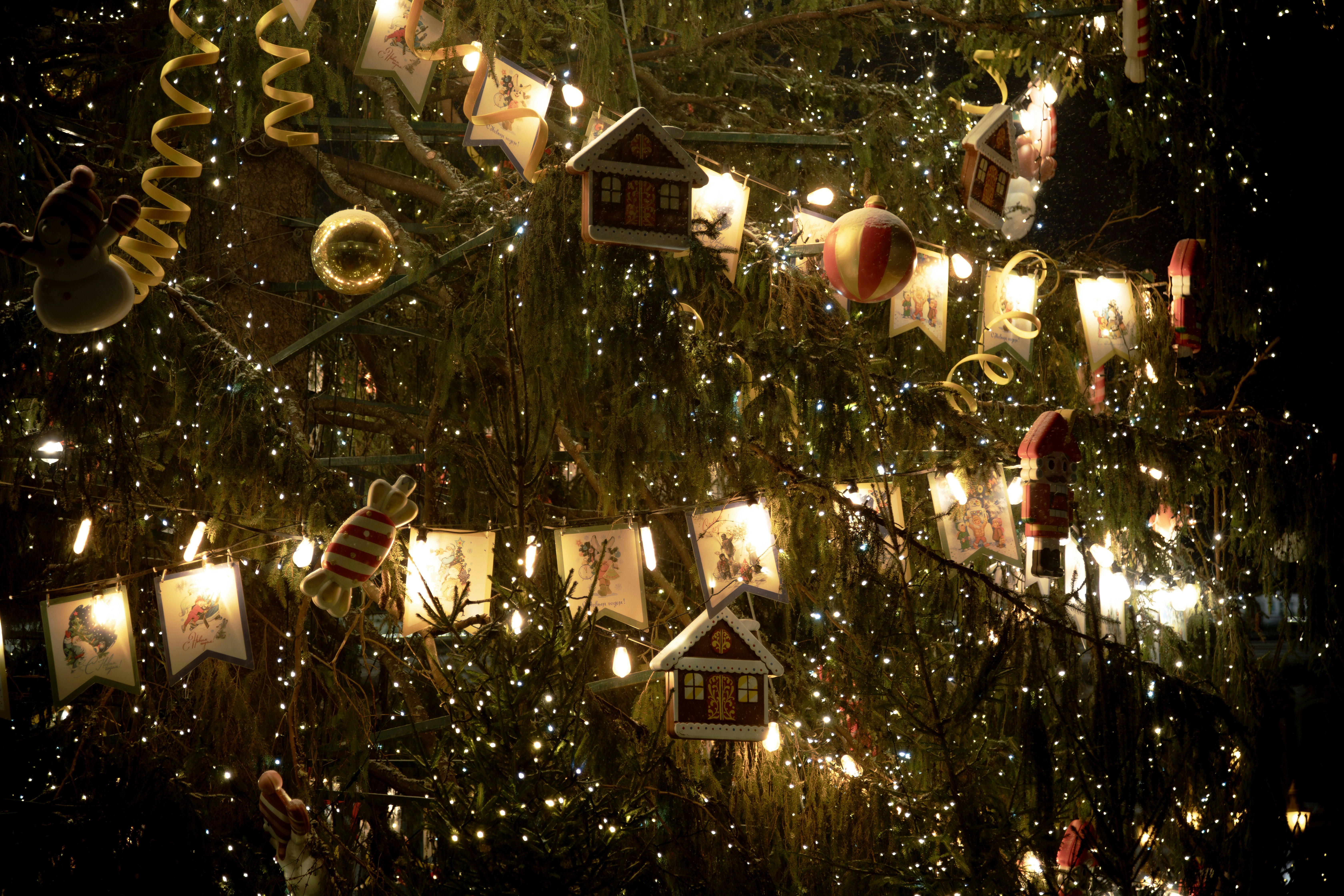 Softly lit holiday tree with hanging lanterns and string lights creating a warm bokeh backdrop. The scene highlights festive decorations and a cozy, intimate atmosphere.