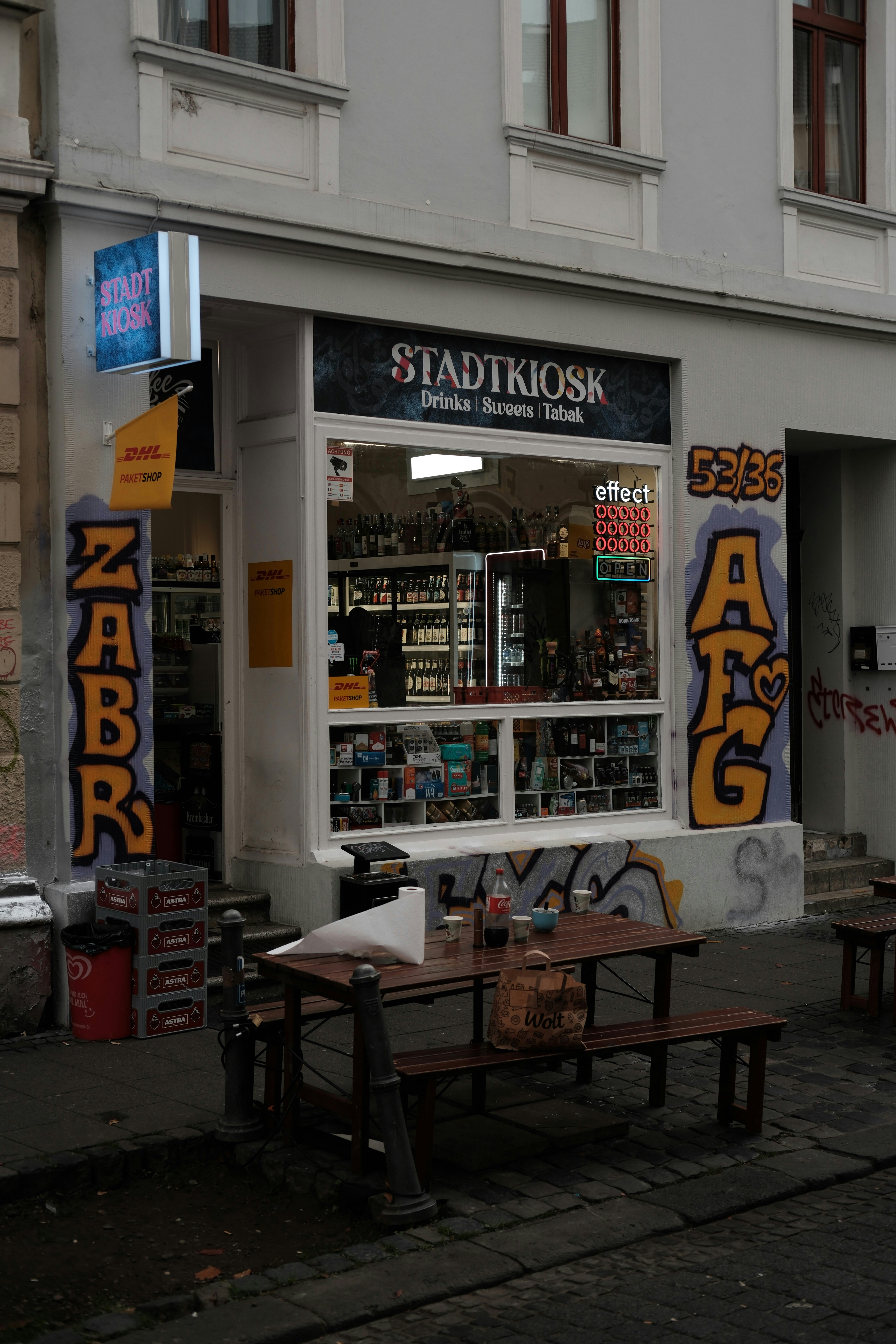 City Shopfront Framed by Graffiti and Outdoor Tables