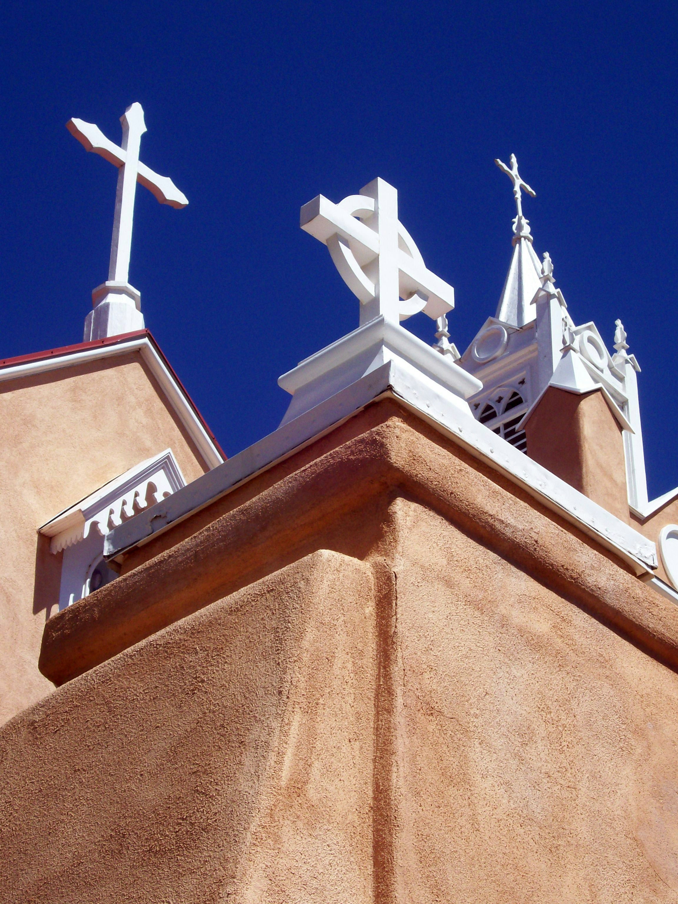 Three crosses atop a tan building against blue sky