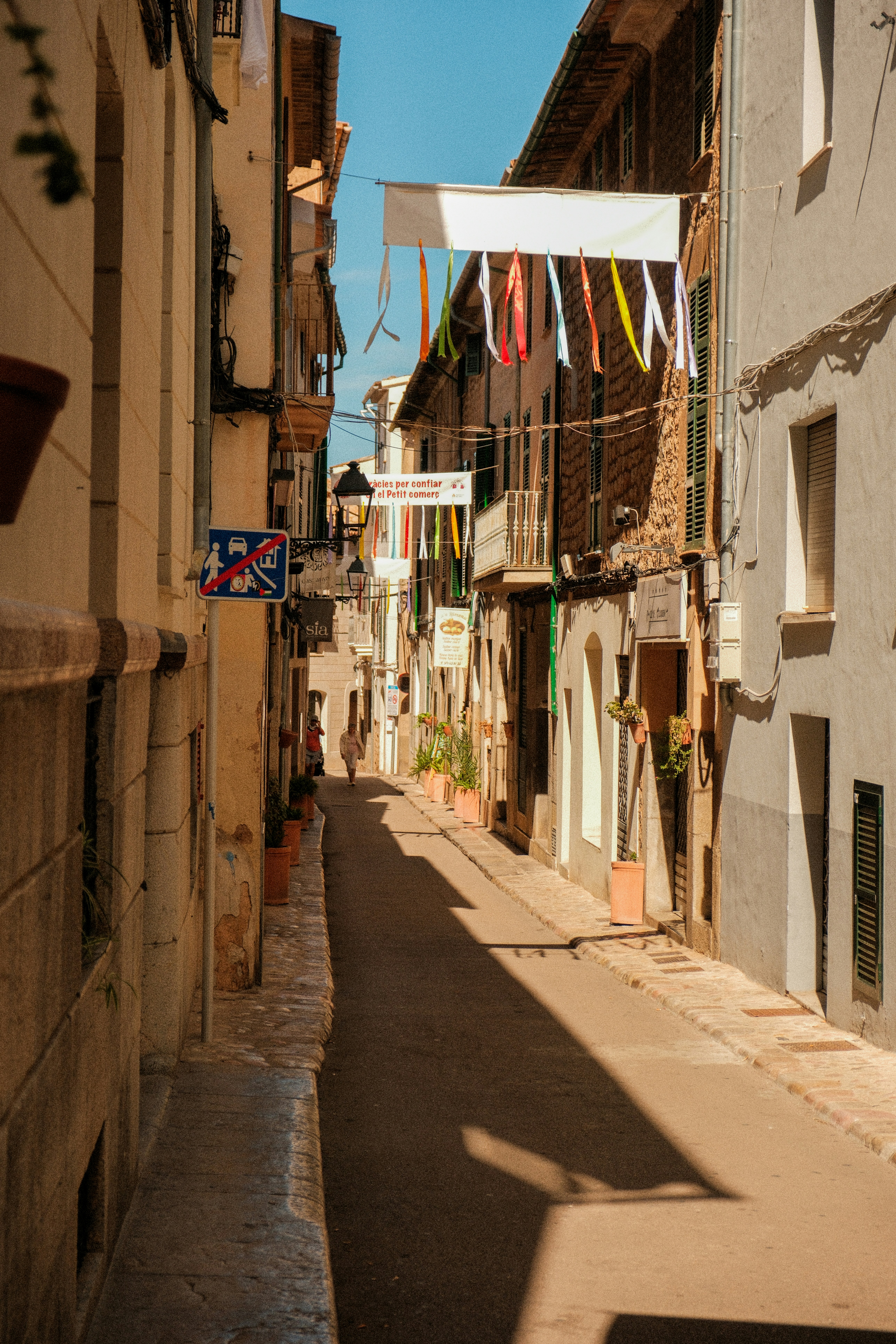 Sunlit alley with fluttering pennant banners in a sun-warmed village street