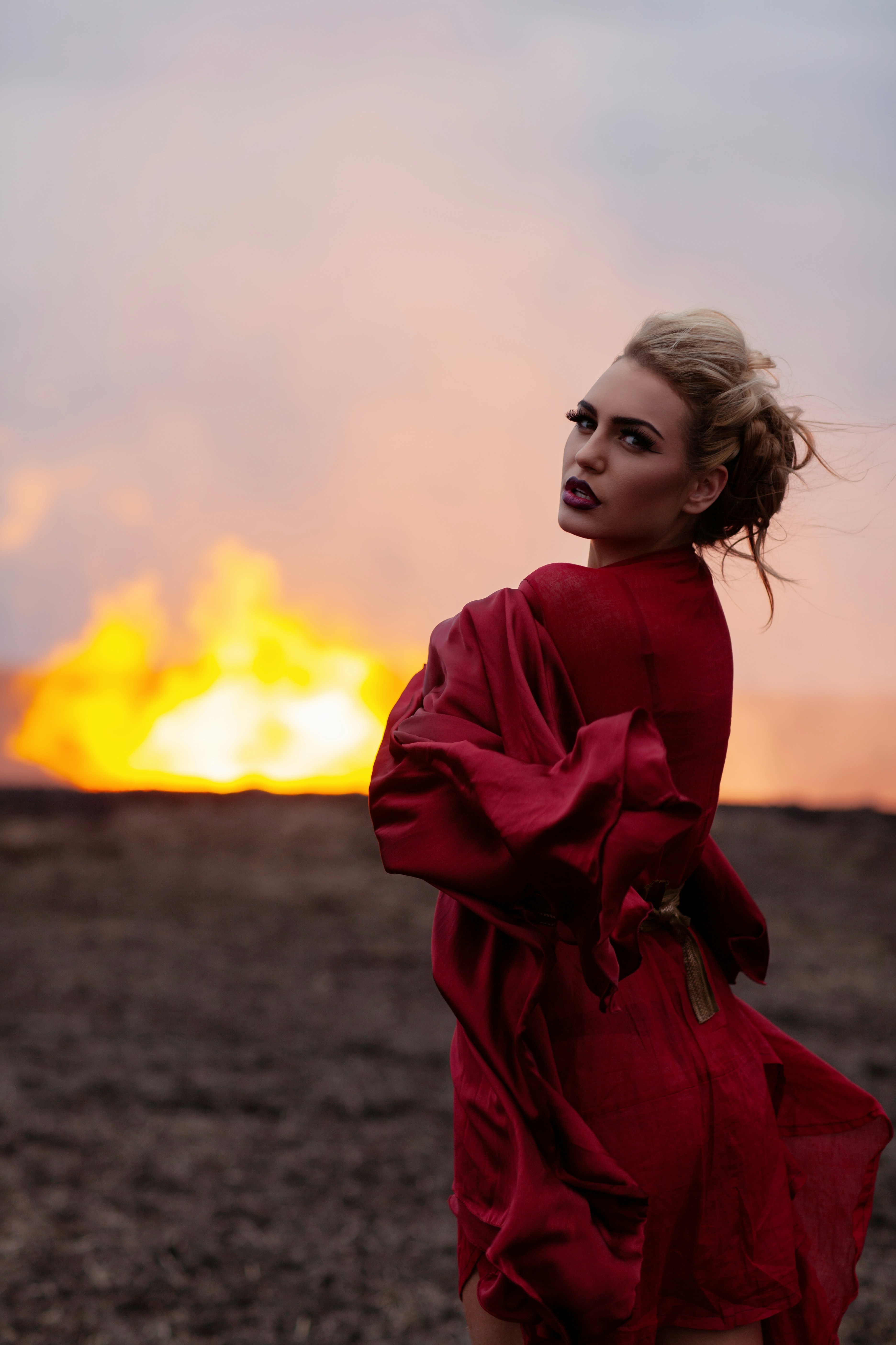 Deserted Prominence: A Woman in Crimson Amid a Fiery Horizon