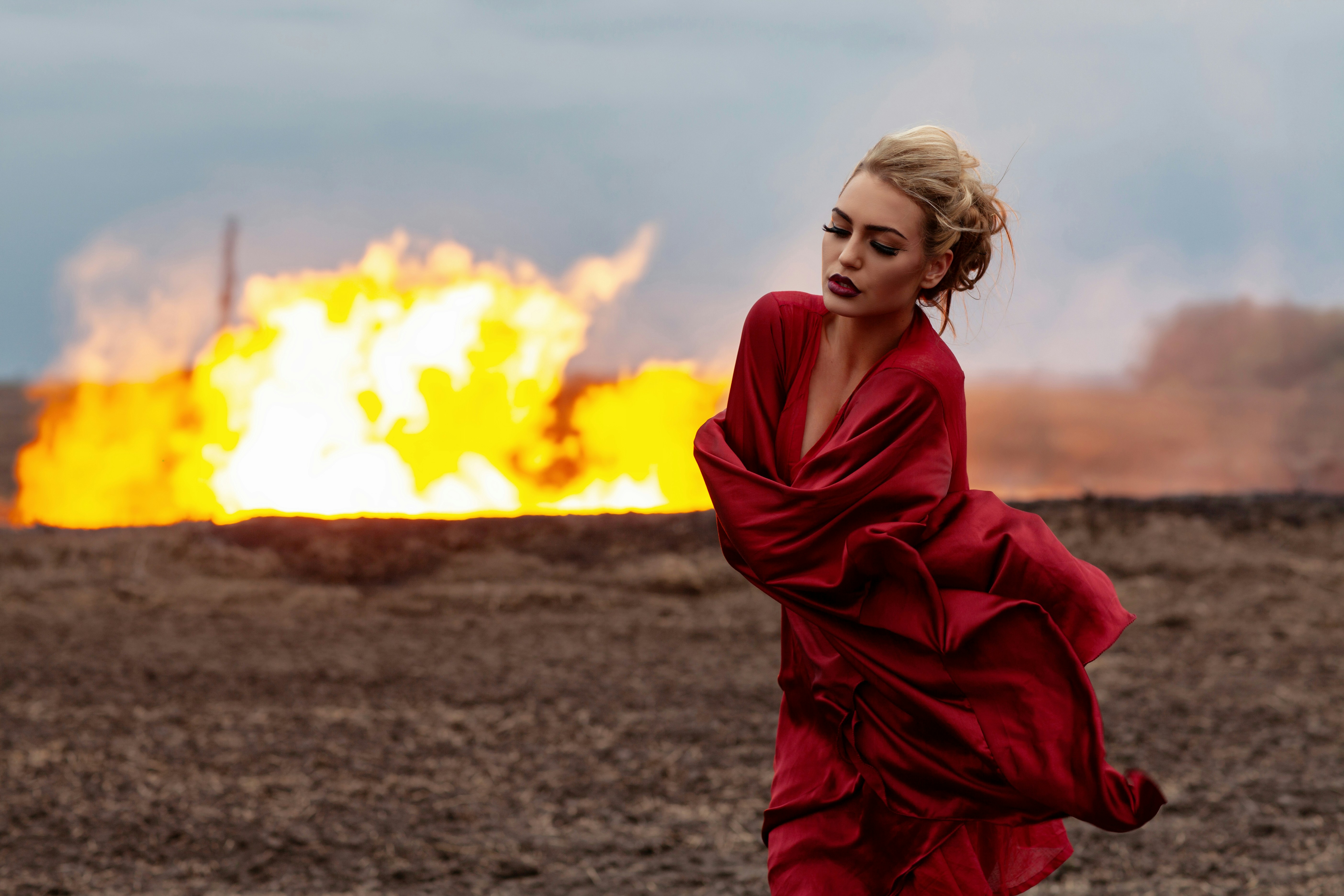 Red Cloak, White Sky: A Woman Moves Past Firelight Across a Desert Plain