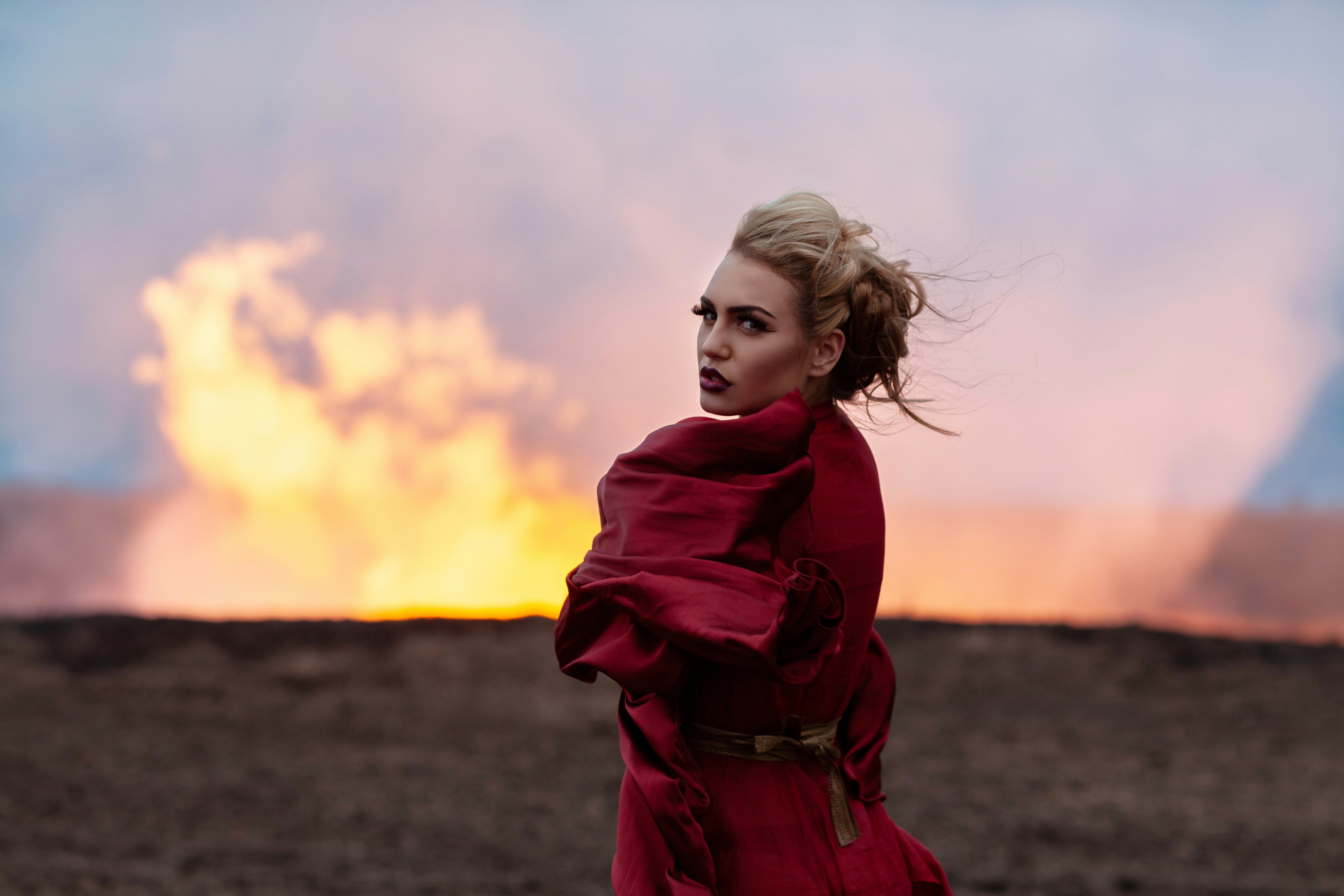  ember in a red cloak against a volcanic horizon