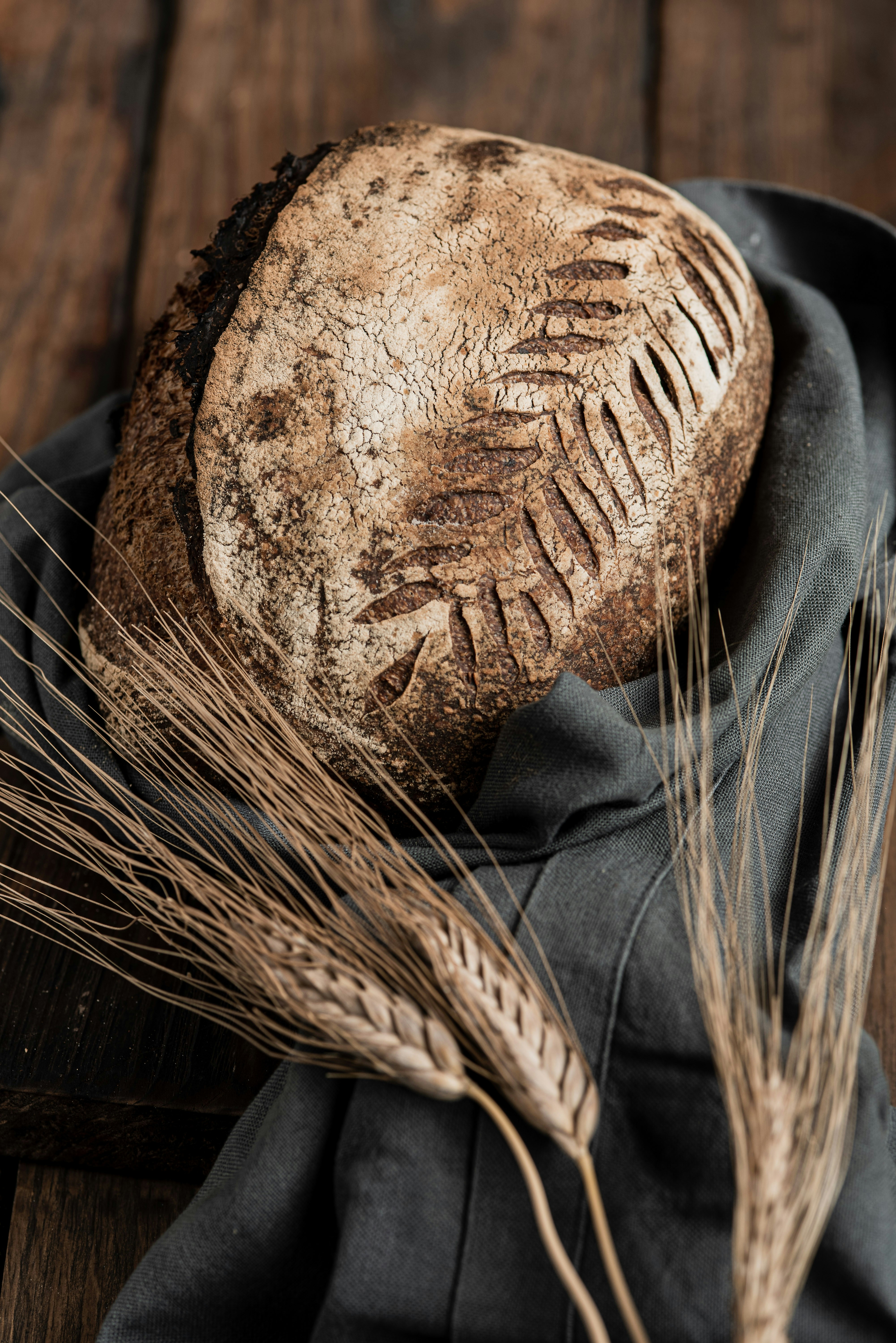 Rustic loaf with stamped pattern resting on a dark cloth