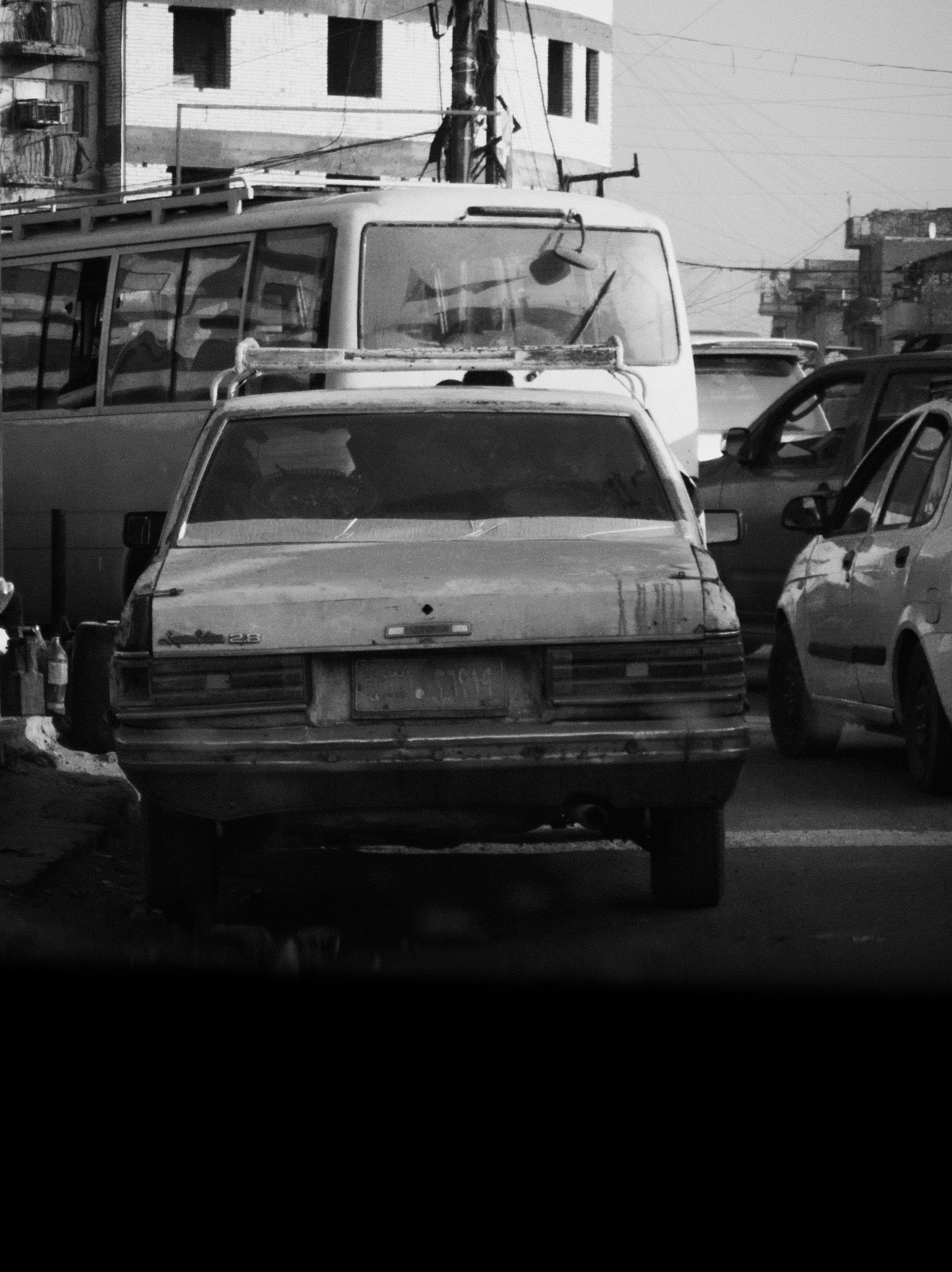 Old car in traffic with bus behind