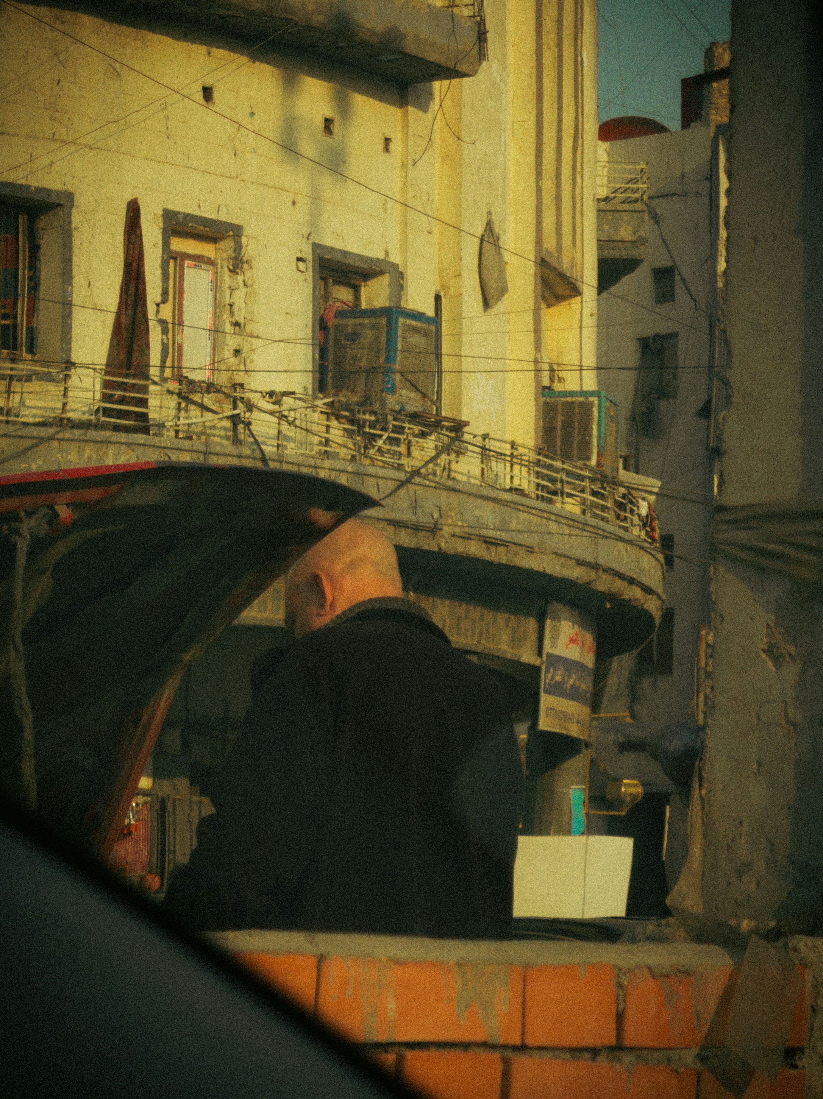 Bald man in black jacket looking at buildings