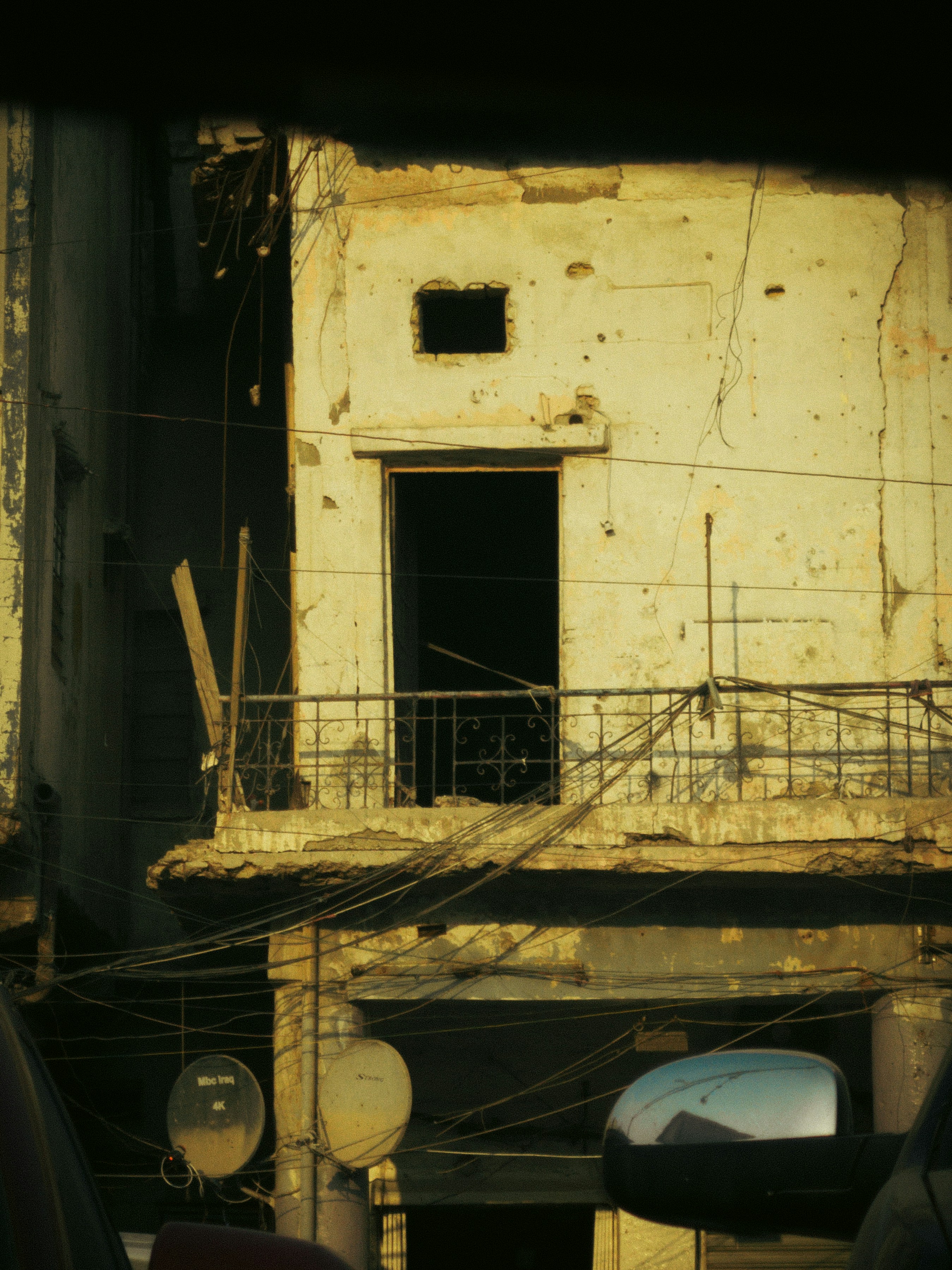 Dilapidated building with satellite dishes and wires.