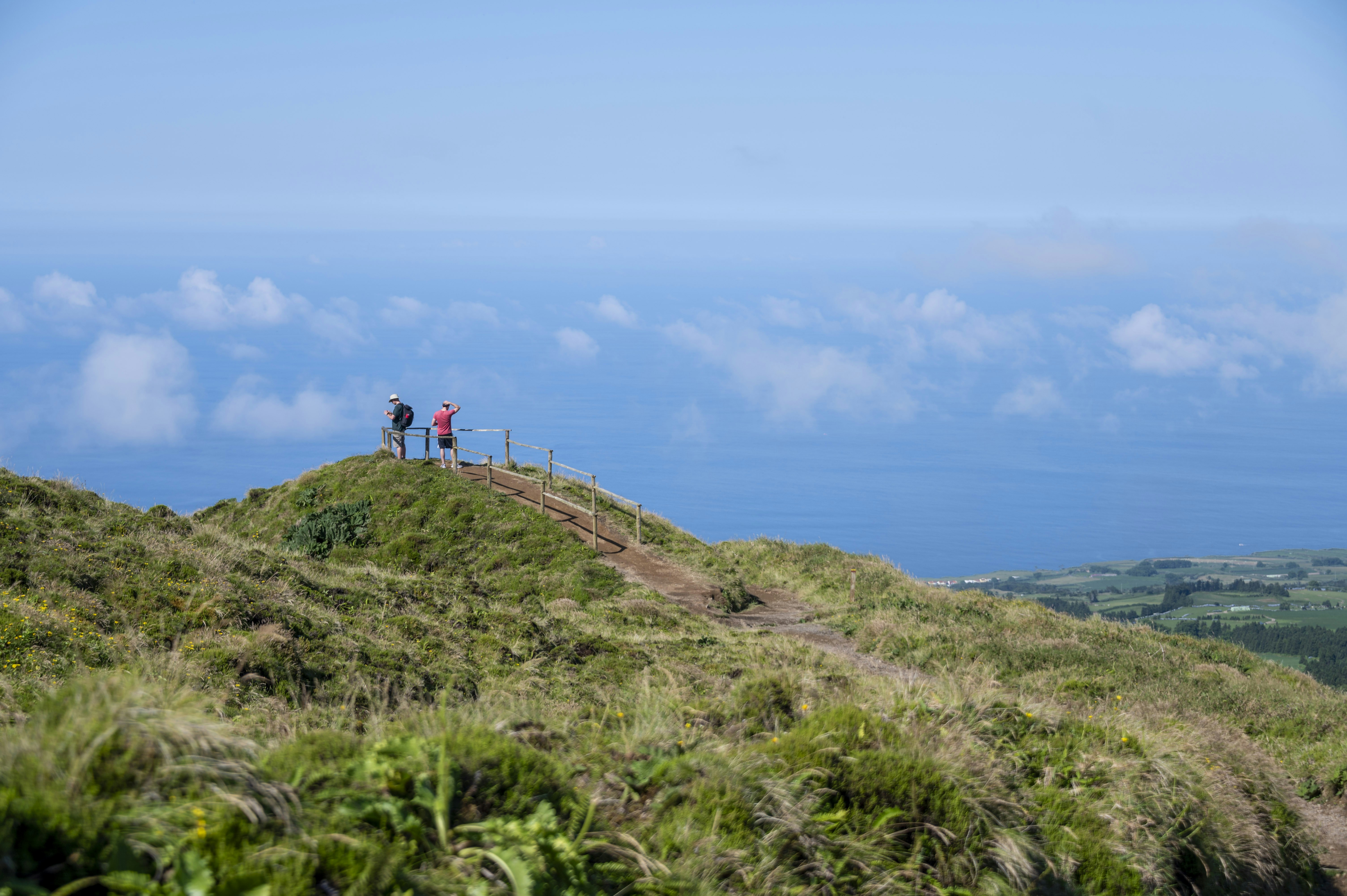 Clifftop Vista: Two hikers at the edge of a grassy promontory