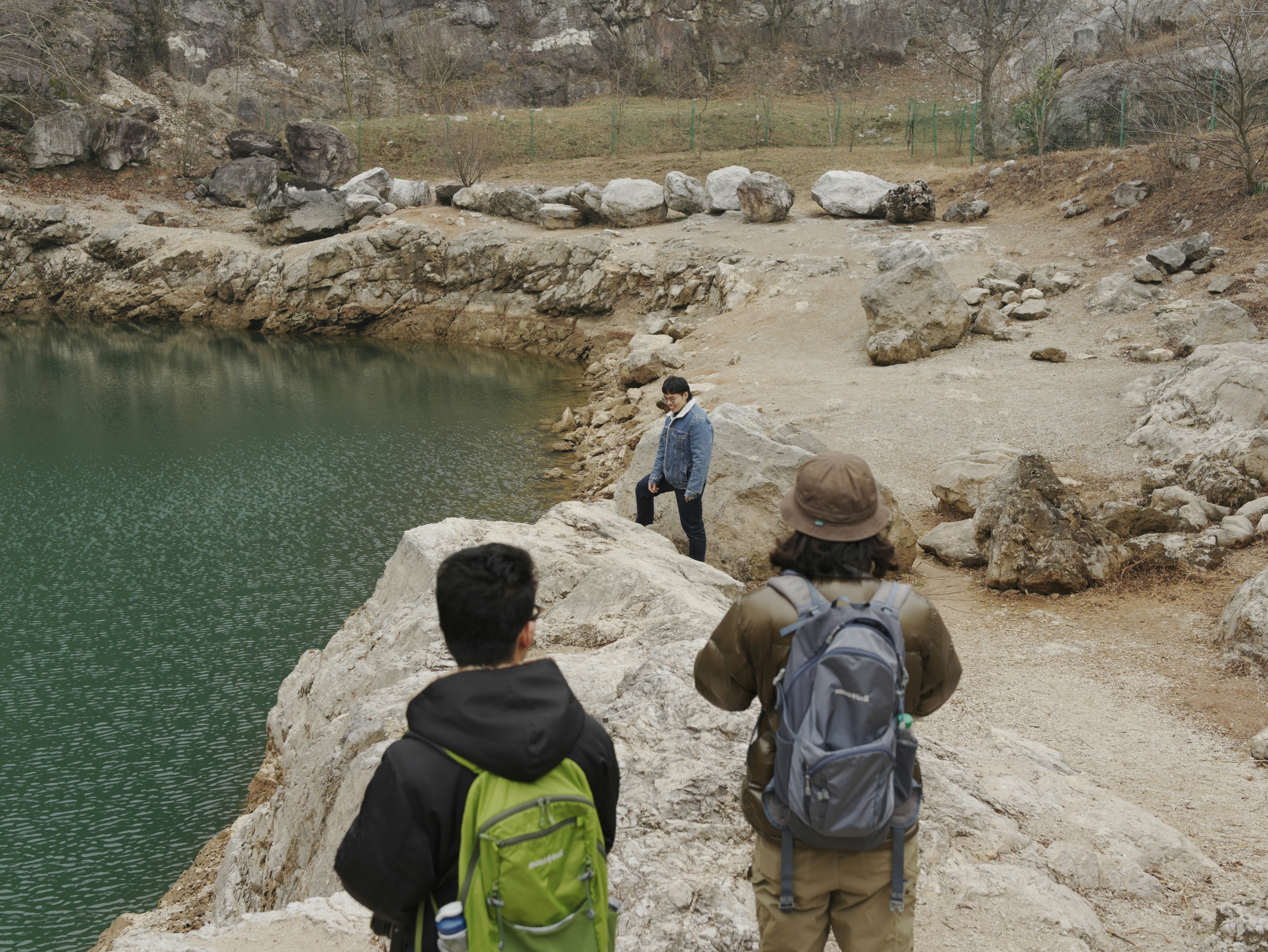 Three Explorers at the Edge of a Quarry Pool