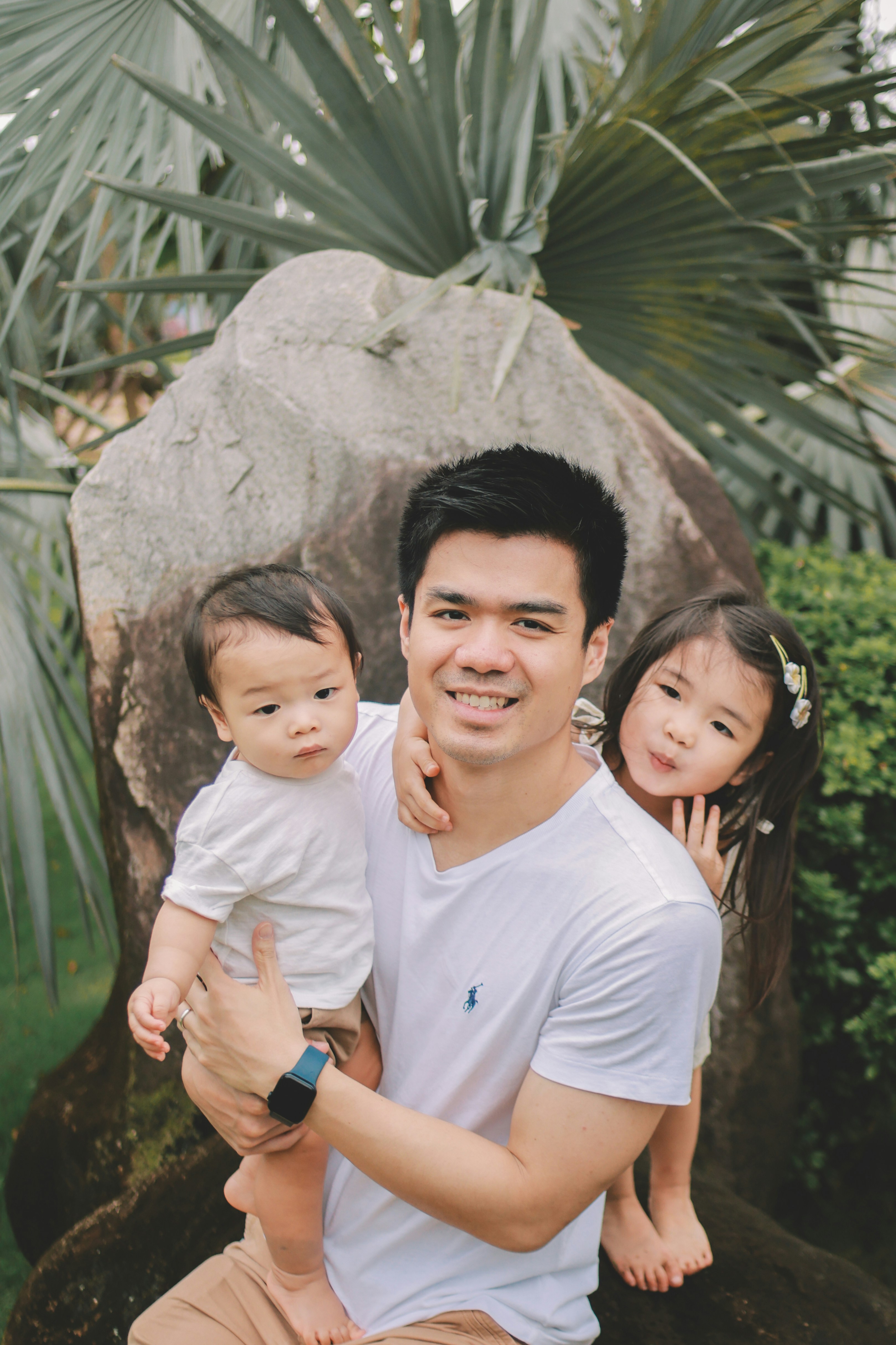 Father's Warm Embrace: A Family Moment Surrounded by Stone and Plant Life