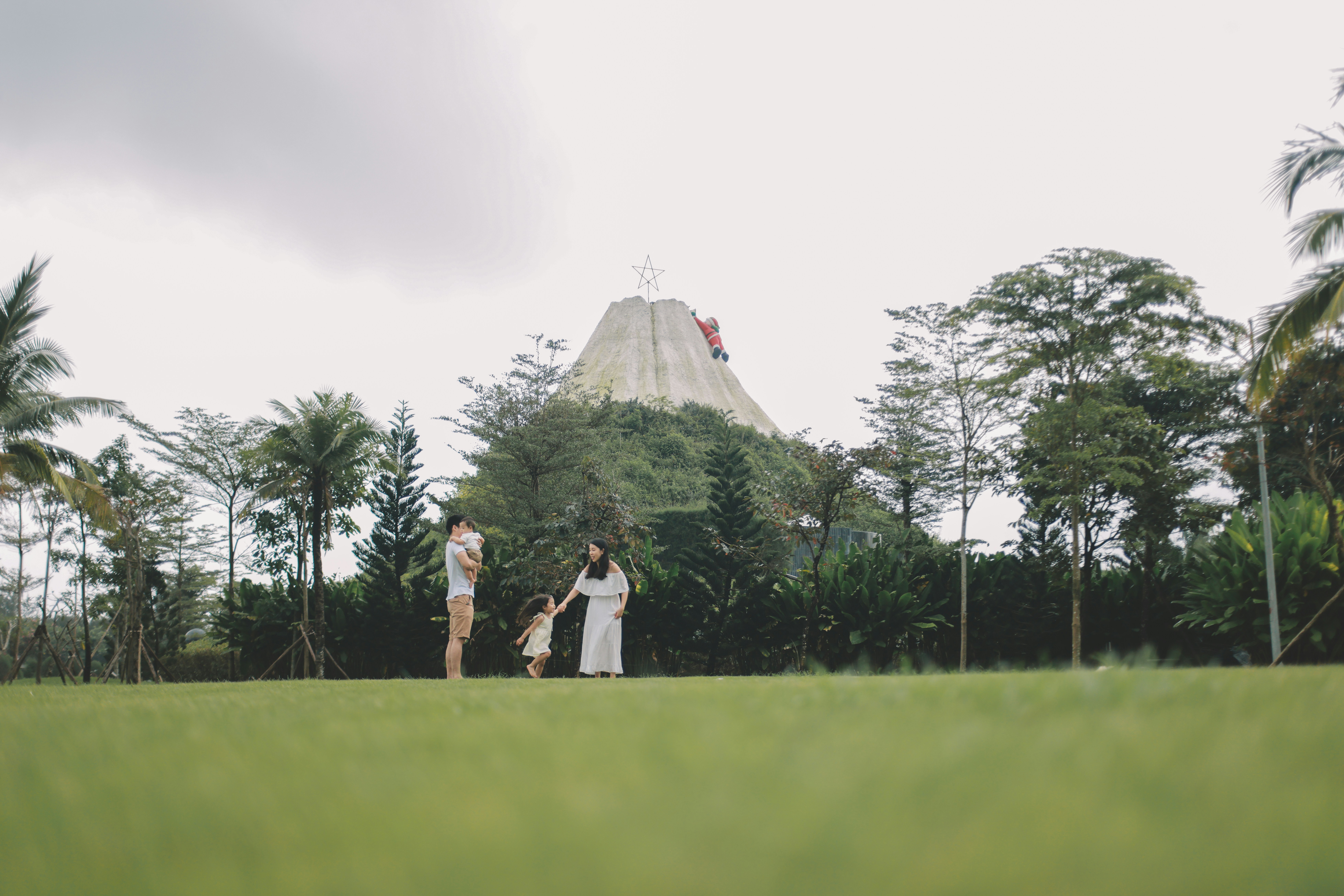 Family poses near a conical structure with trees. photo – Free Family ...