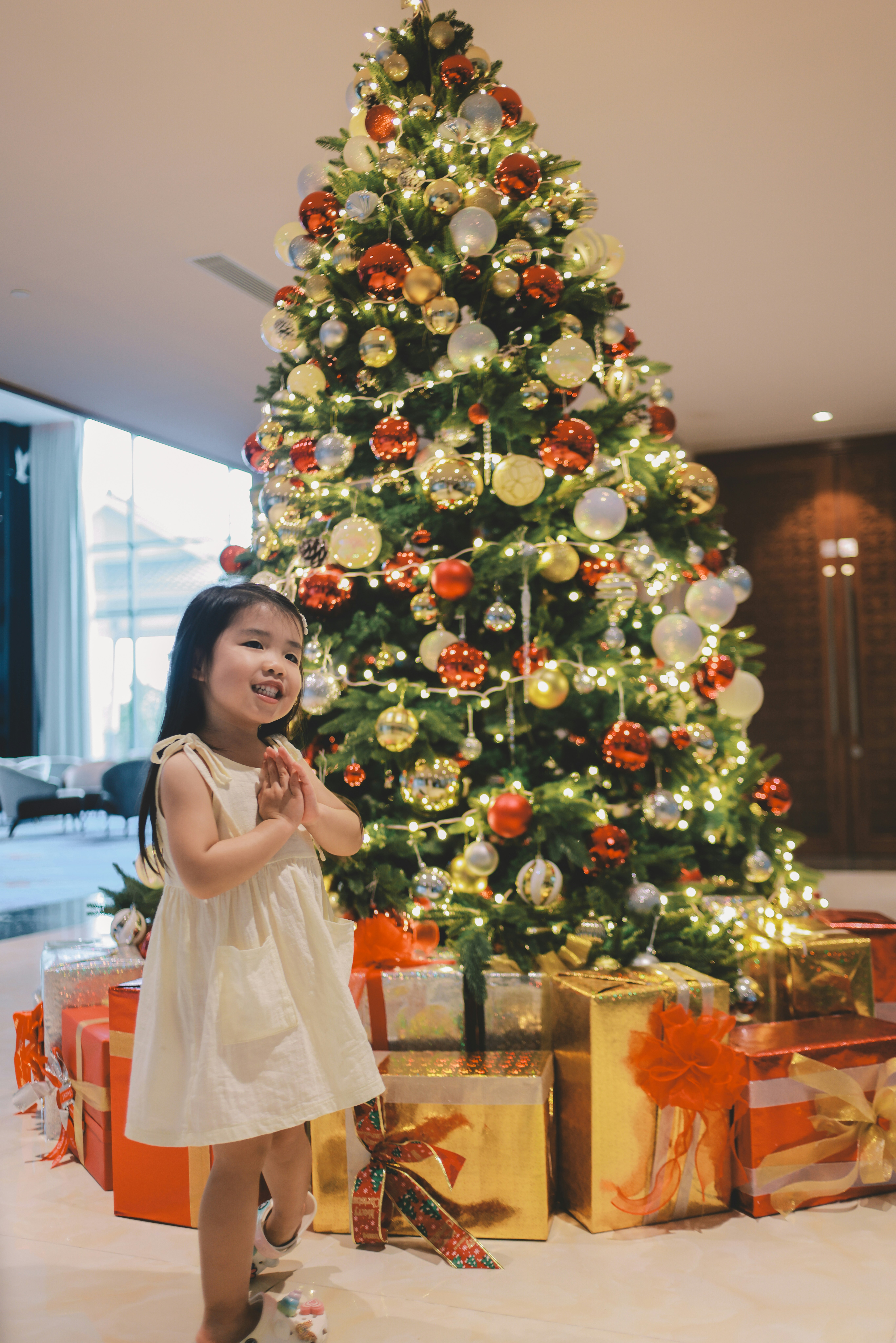 Girl in White Dress Delights at the Christmas Tree