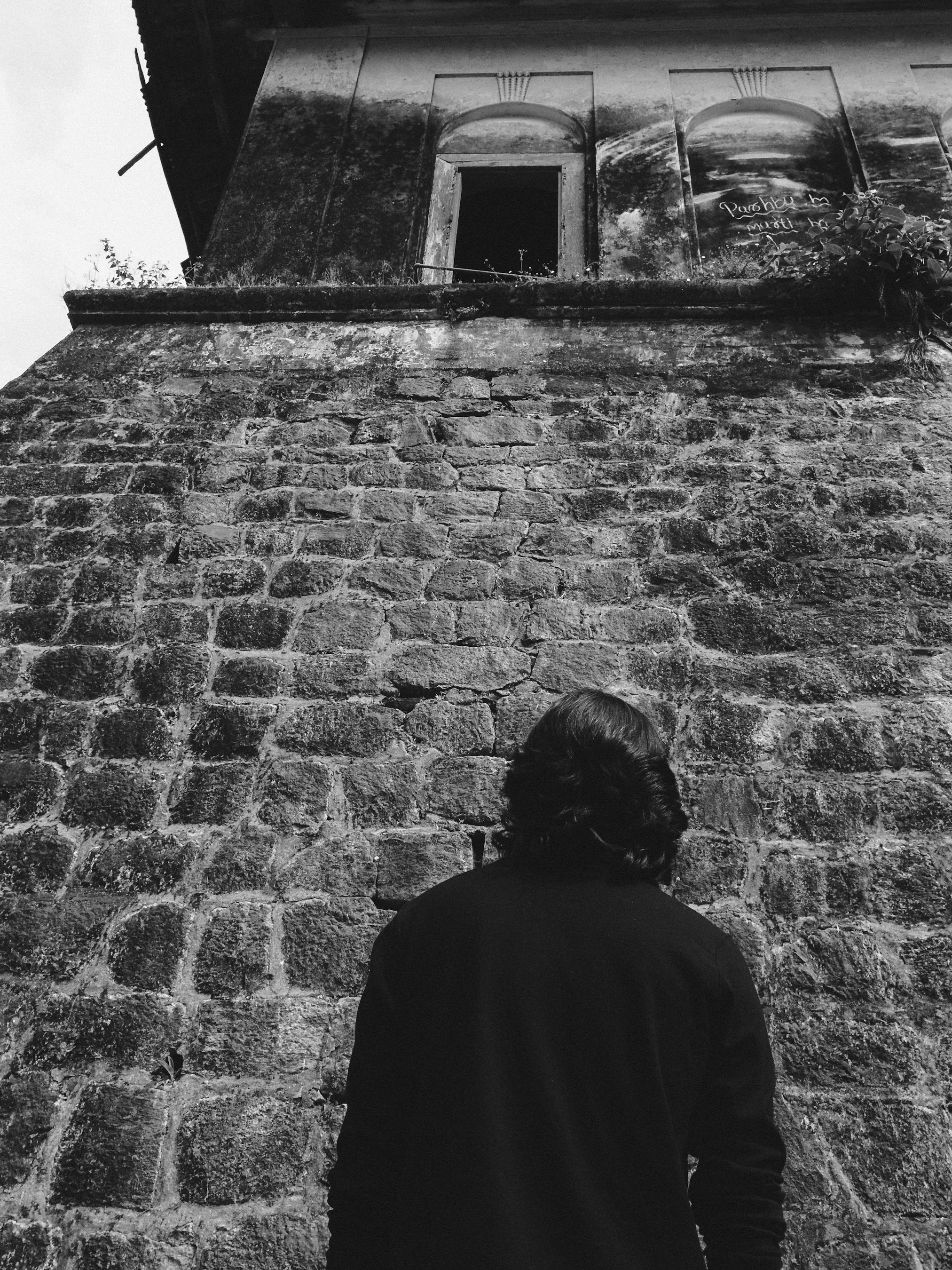Person looking up at an old stone building