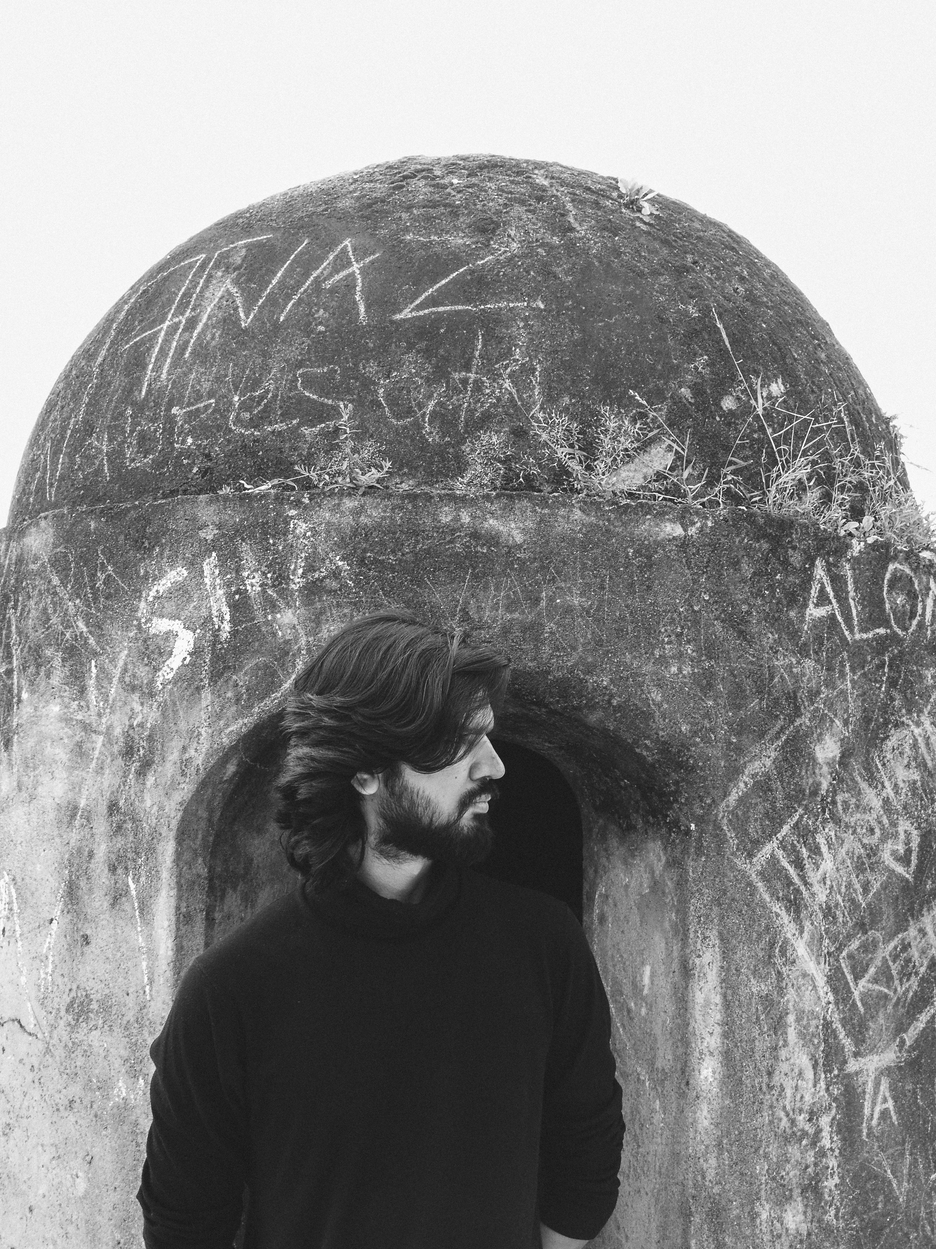 Man standing in front of graffiti-covered dome structure