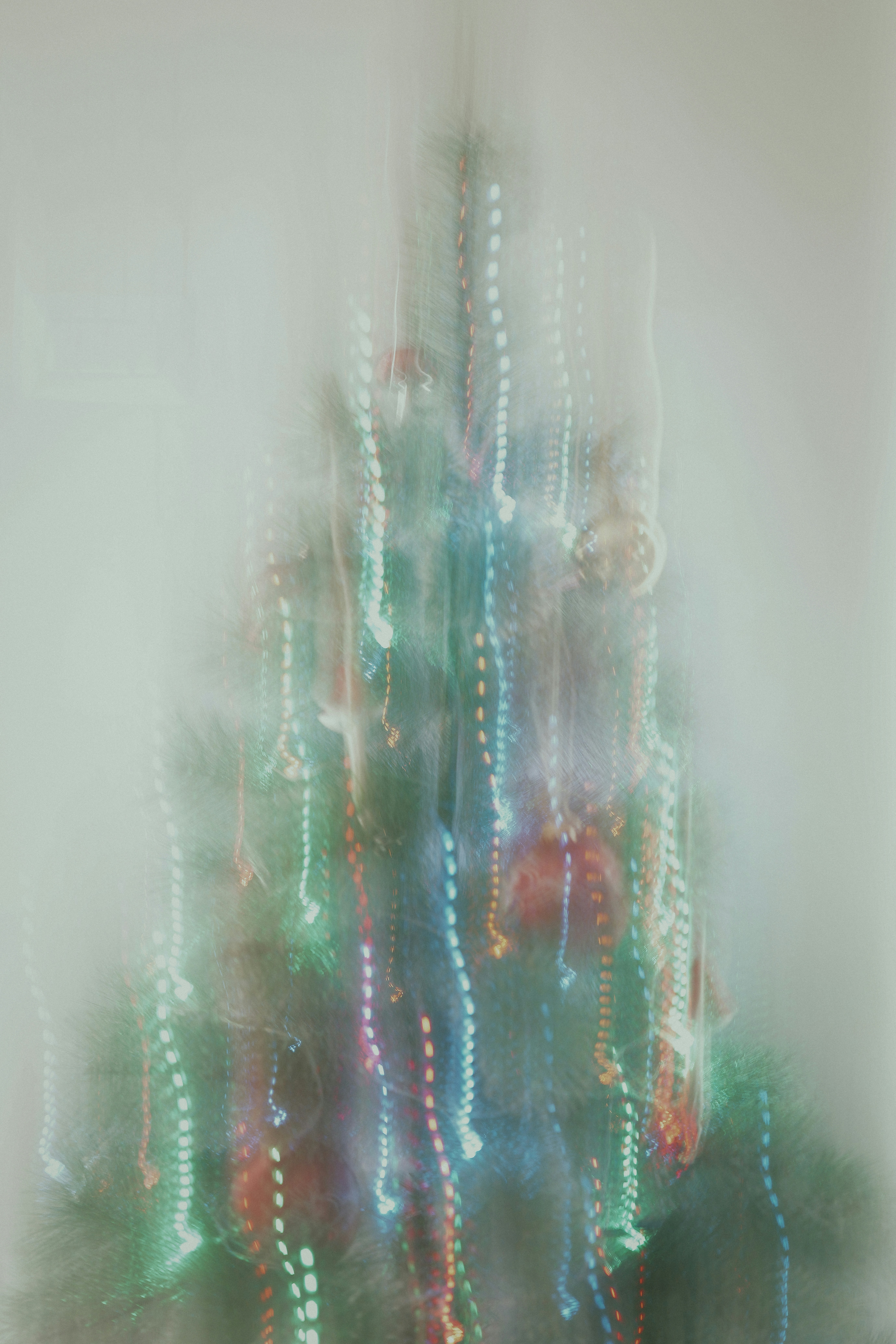 A Christmas tree dissolves into cascading multicolor light trails. Dynamic motion blur and rich hues convey energy, celebration, and a festive indoor mood.