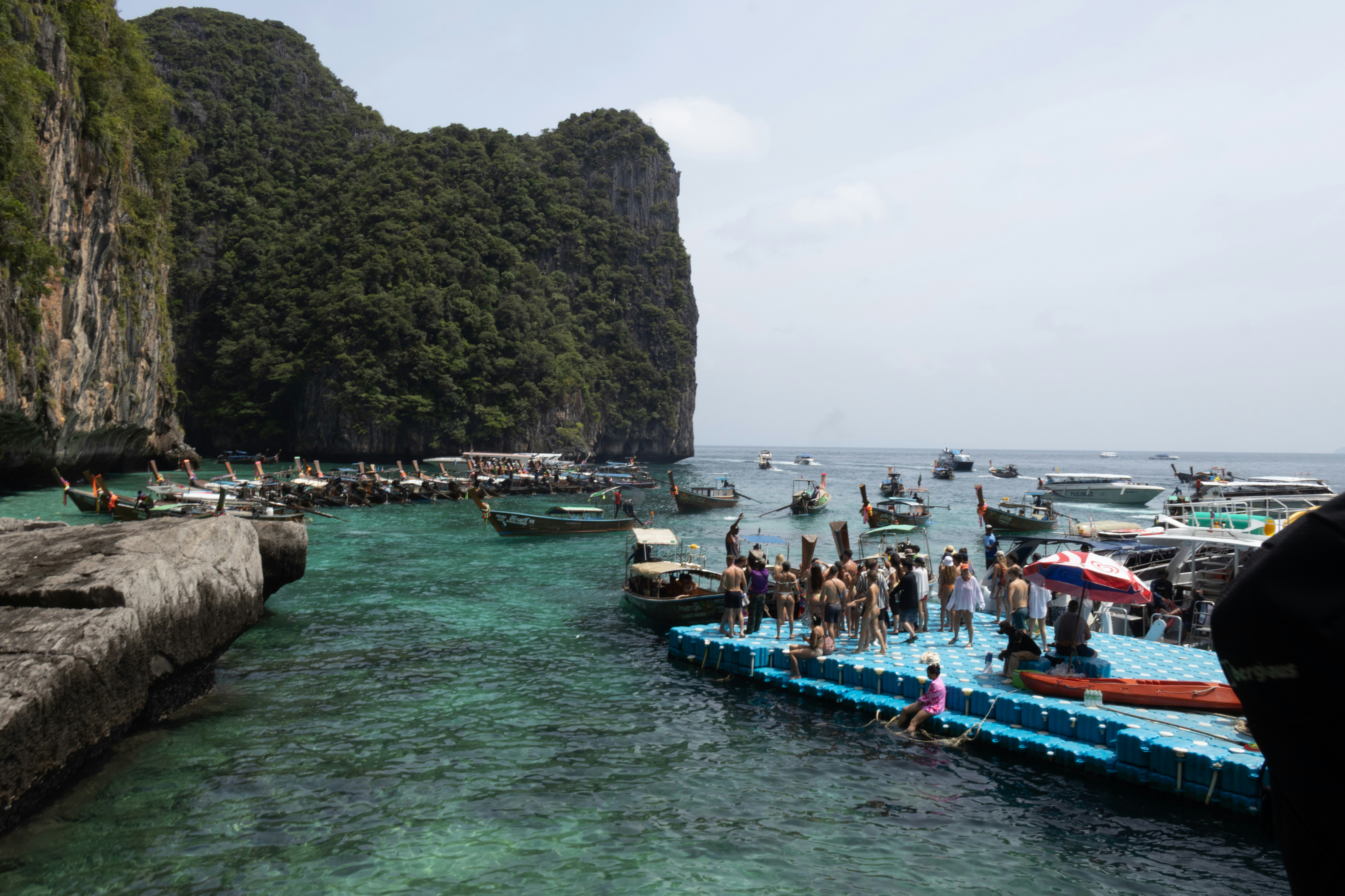 Harbor of People and Boats at a Limestone Cliff Bay