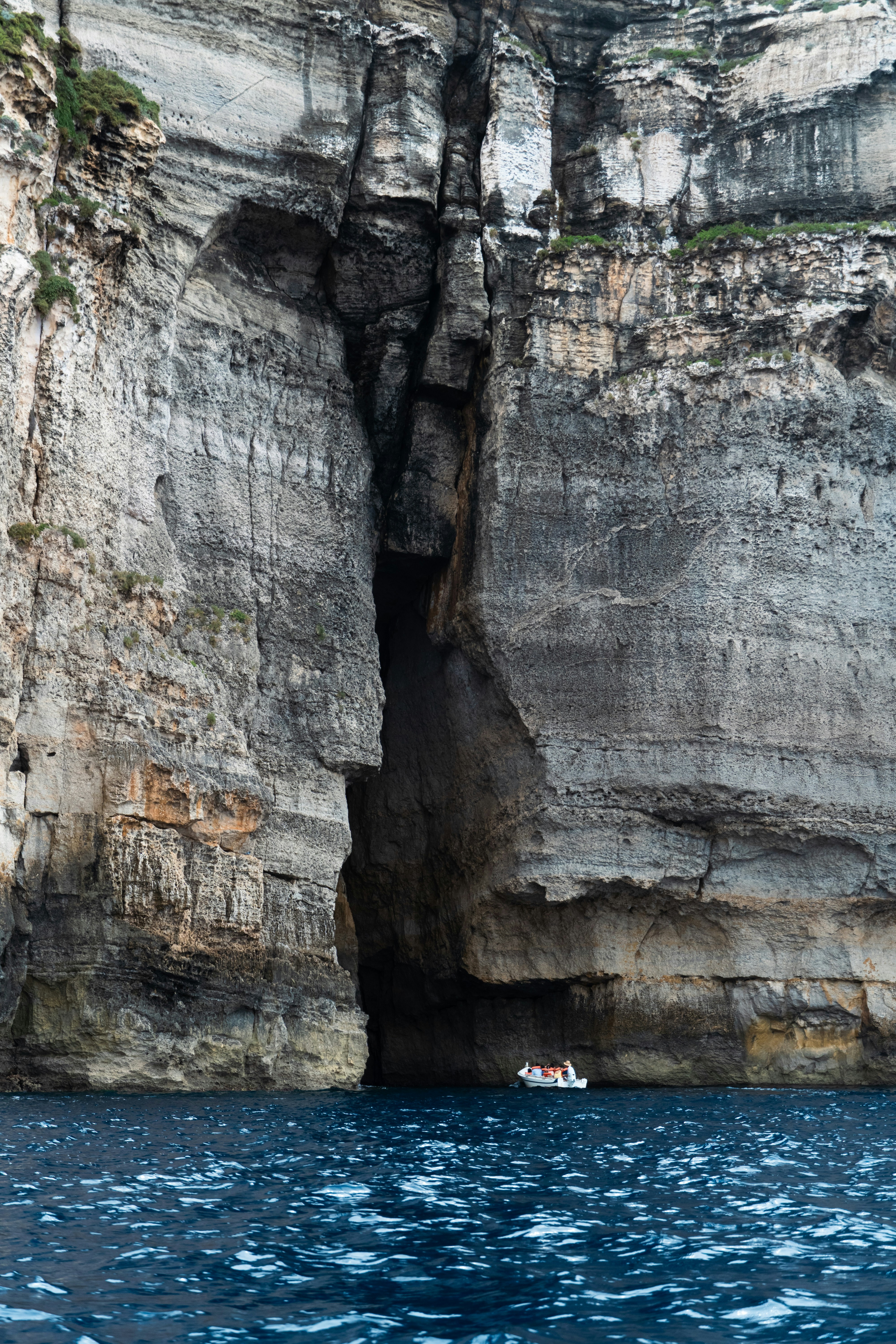 Seafloor Gate: A Boat at the Base of a Towering Cliff