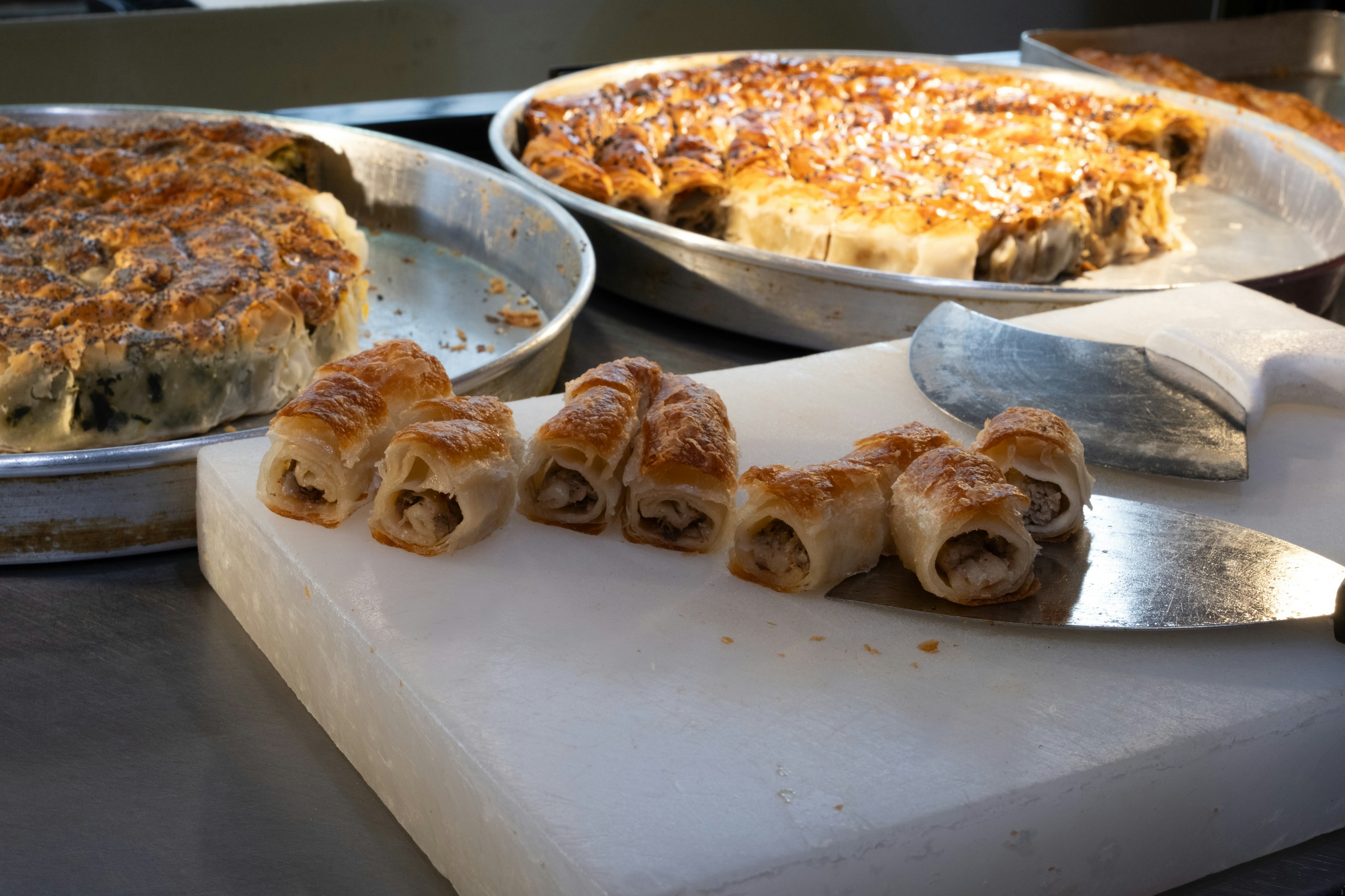 Golden Bites on a Marble Platter: Pastry Rolls with Savory Pies in the Background