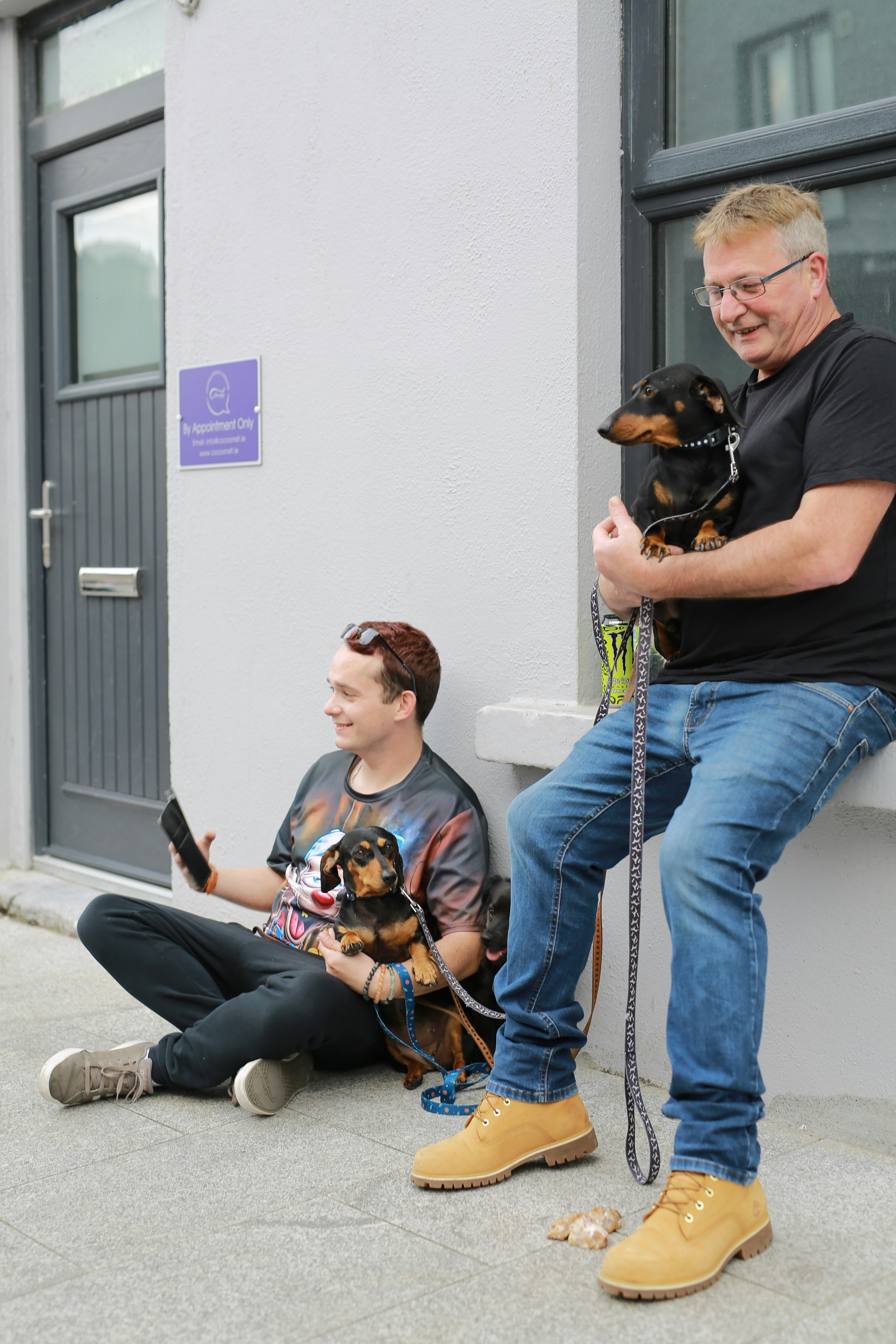 Two Friends and a Pair of Doxies: Quiet Moment Outside a Building