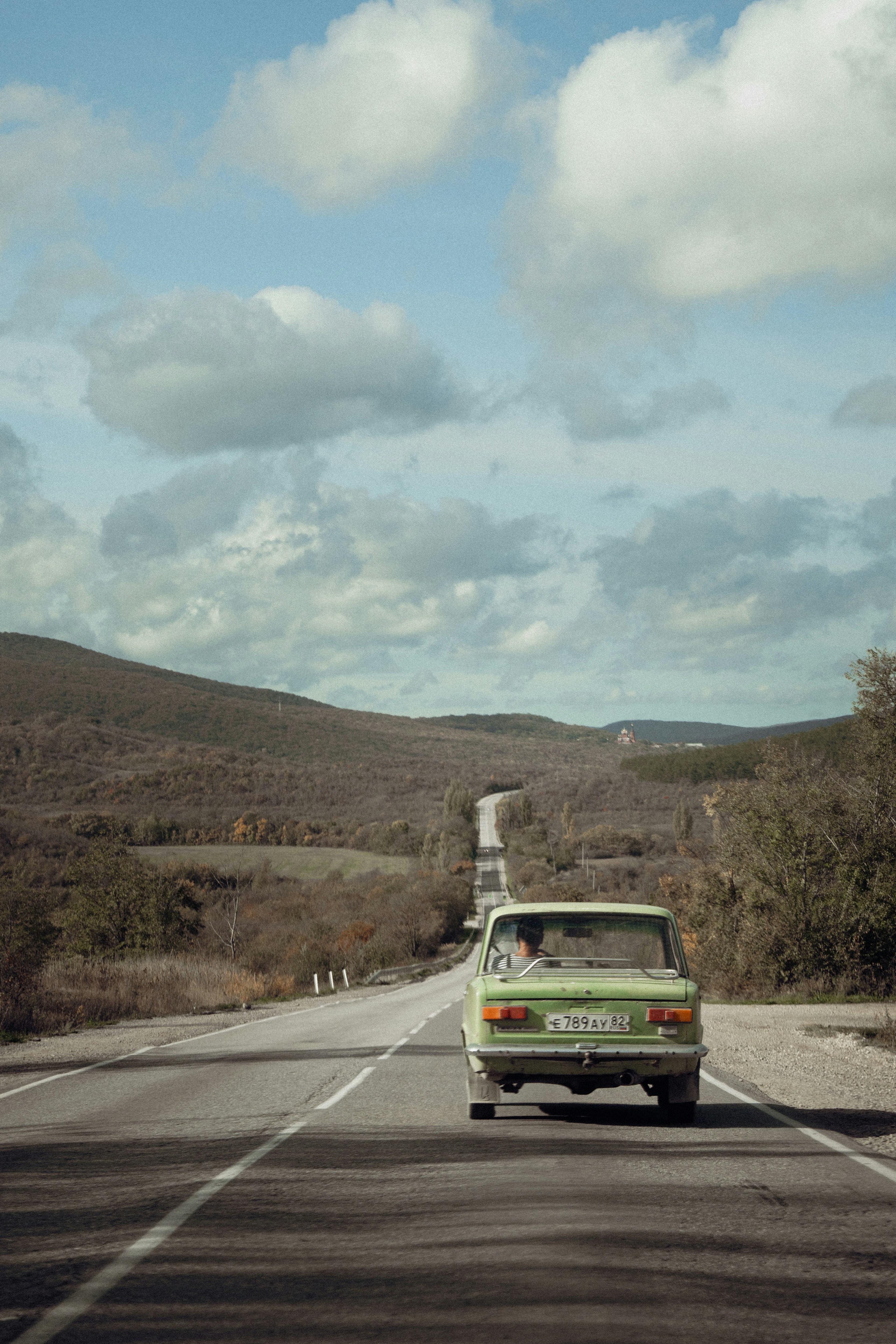 Dusty Highway Rewind: Green Soviet Sedan on a Long Deserted Road