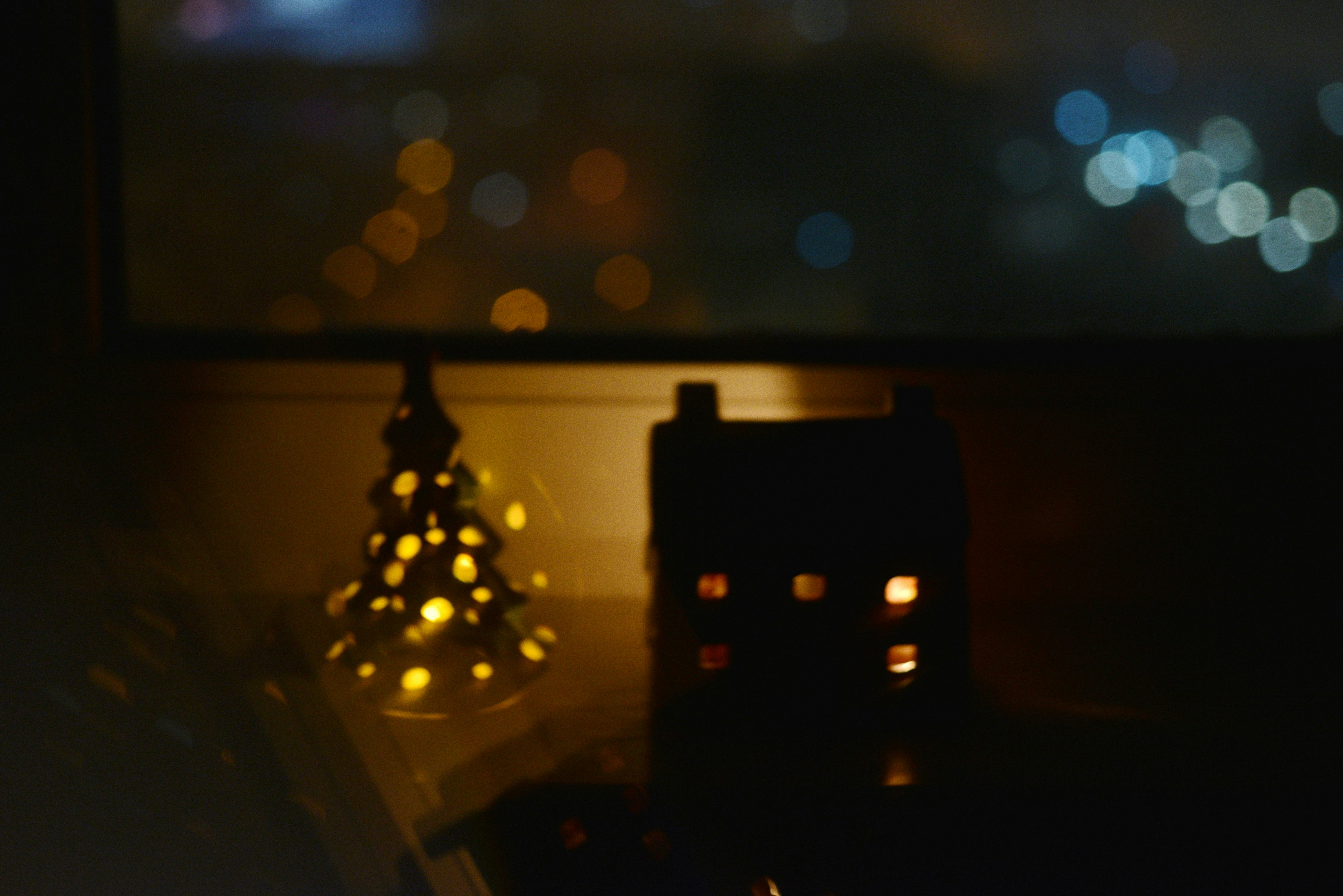 Cozy Nightscape: Warm Glow from Miniature House Against City Lights
