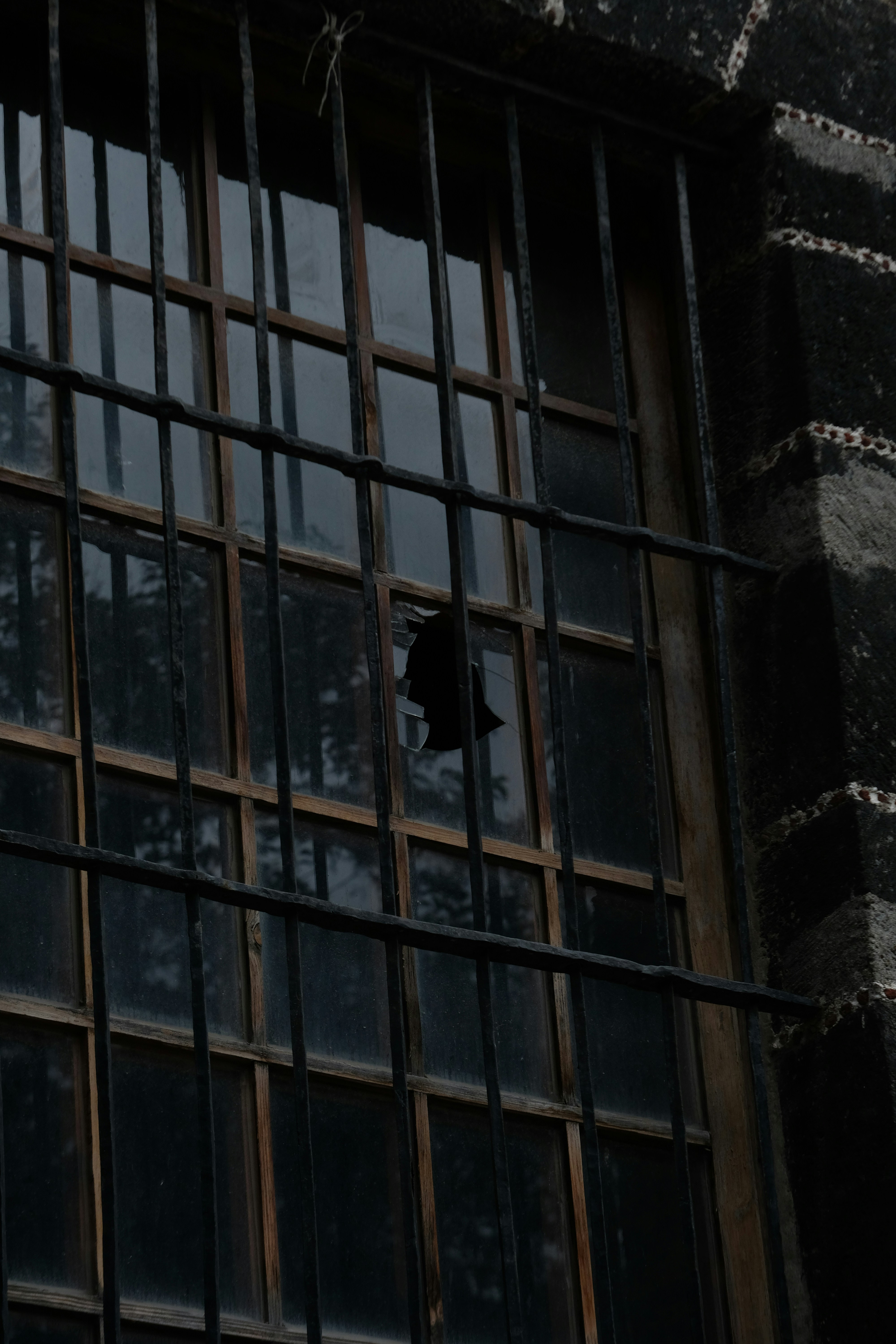 Broken Window Behind Iron Grille: An Old Building’s Silent Veil