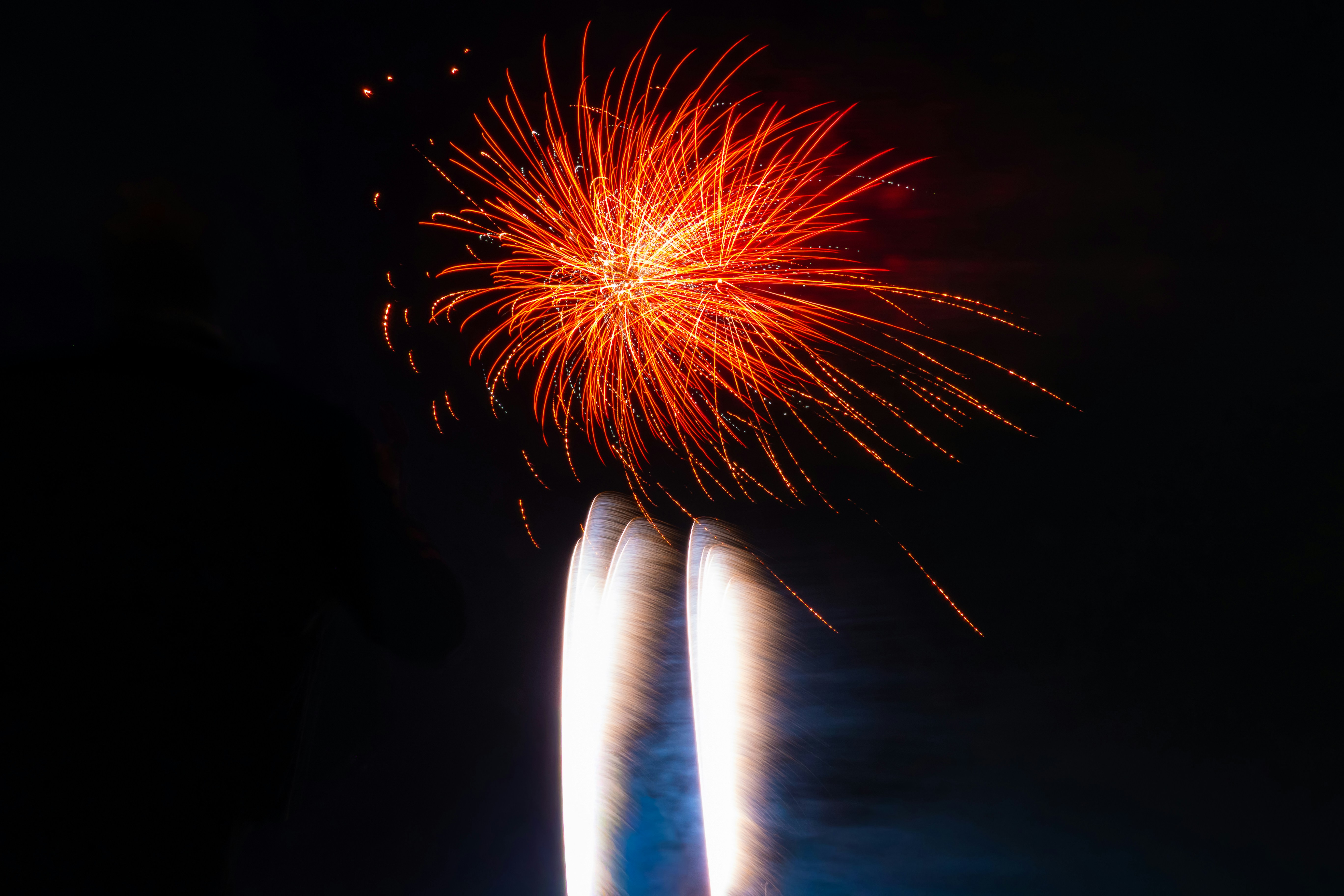 Burst Above the Twin Streaks: Fireworks Over Night Skies