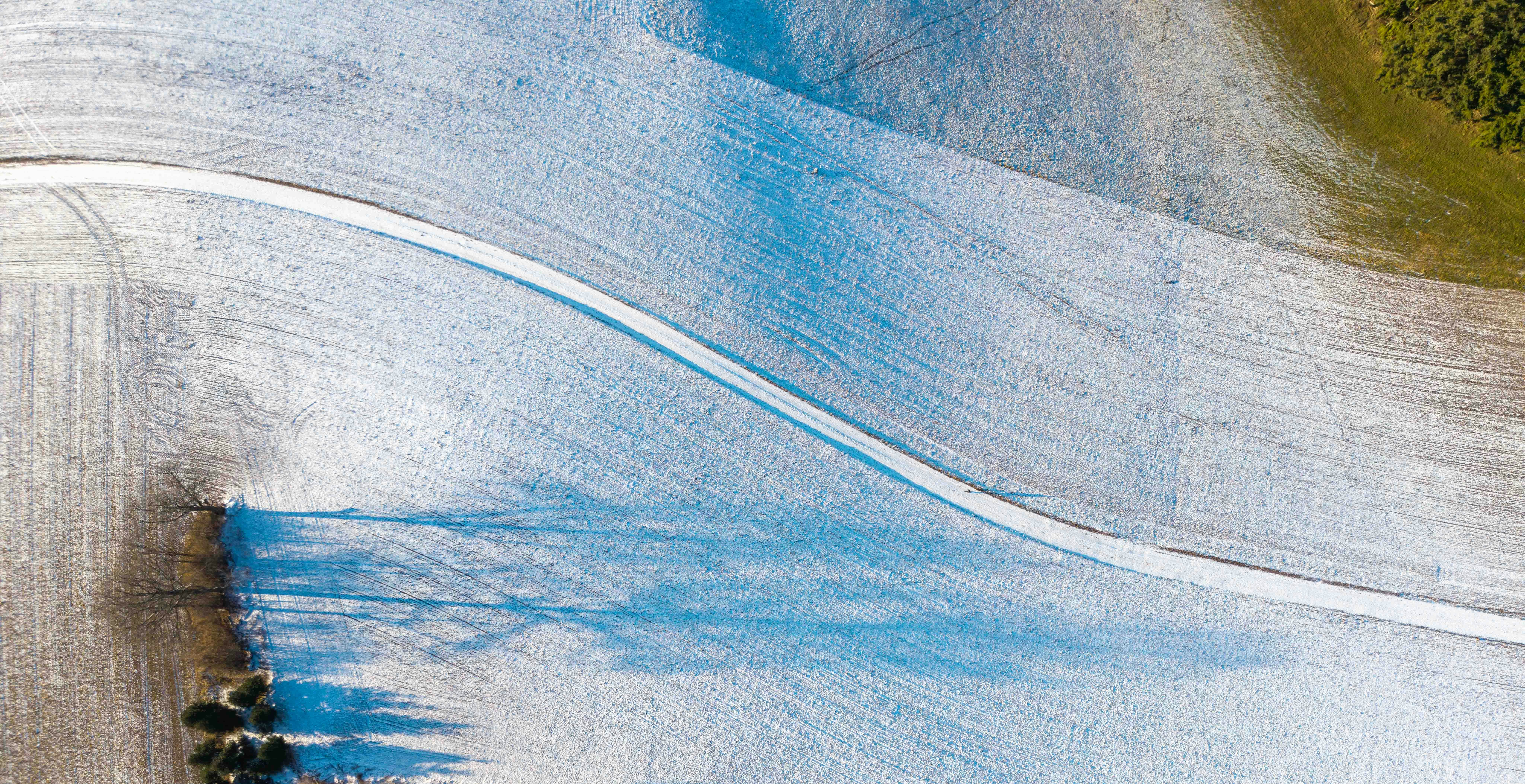 Snow-Cacked Slope and Winding Road: Aerial Veil over Frozen Field