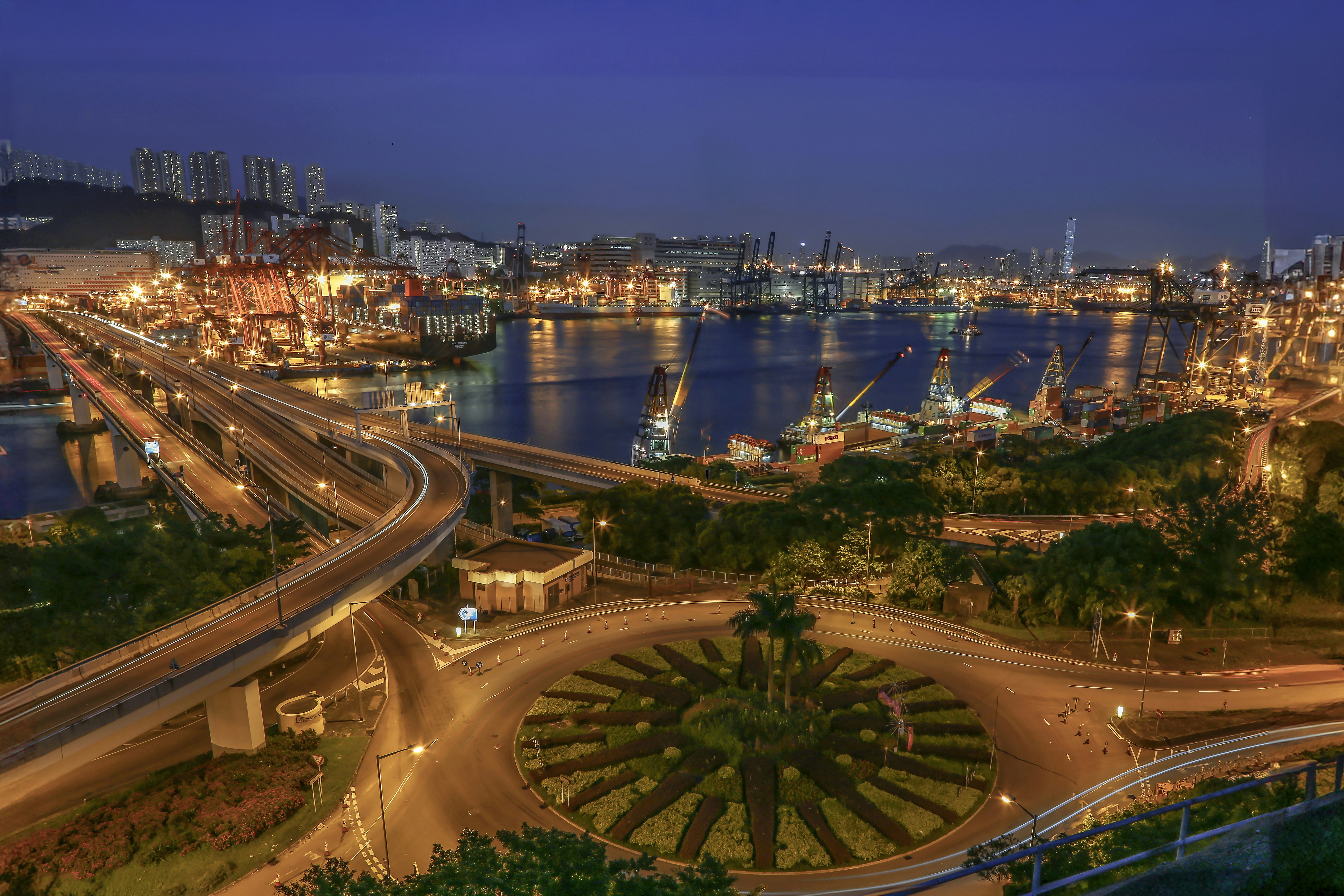 Nighttime Harbor Circles: Aerial Roundabout Framed by Cranes and Water