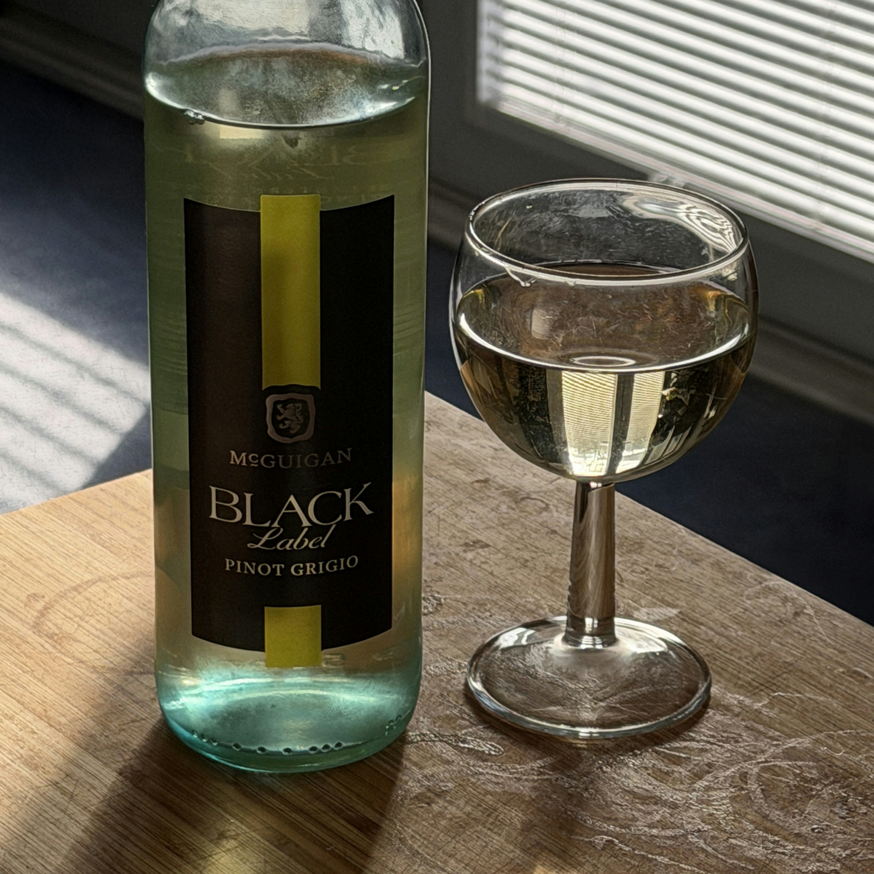 Quiet Pour: A bottle of White Pinot Grigio Beside a Glass on a Wooden Table