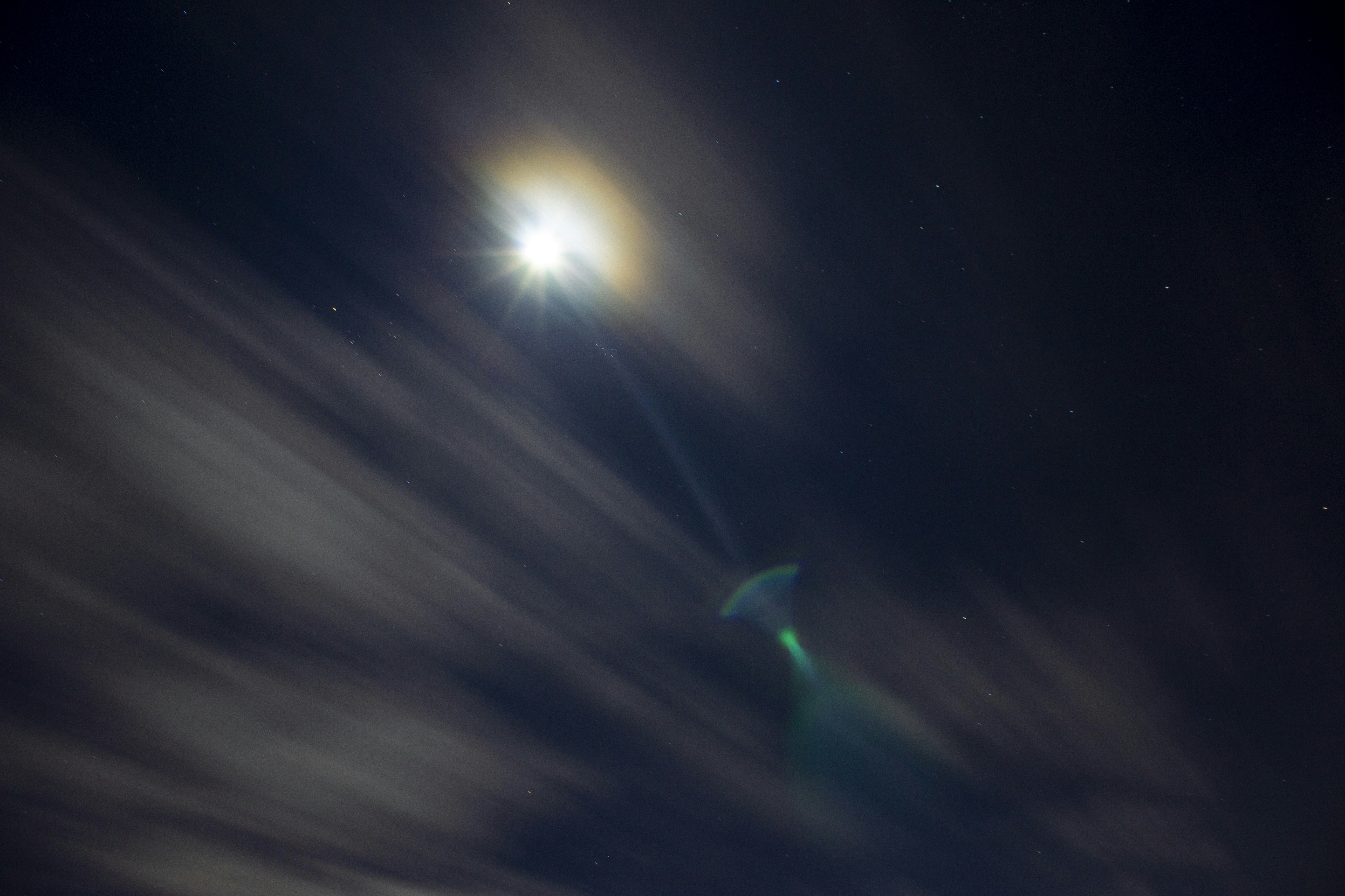 Moonlit Trails: Clouds Drift Across a Starry Night with a Ghostly Nebula