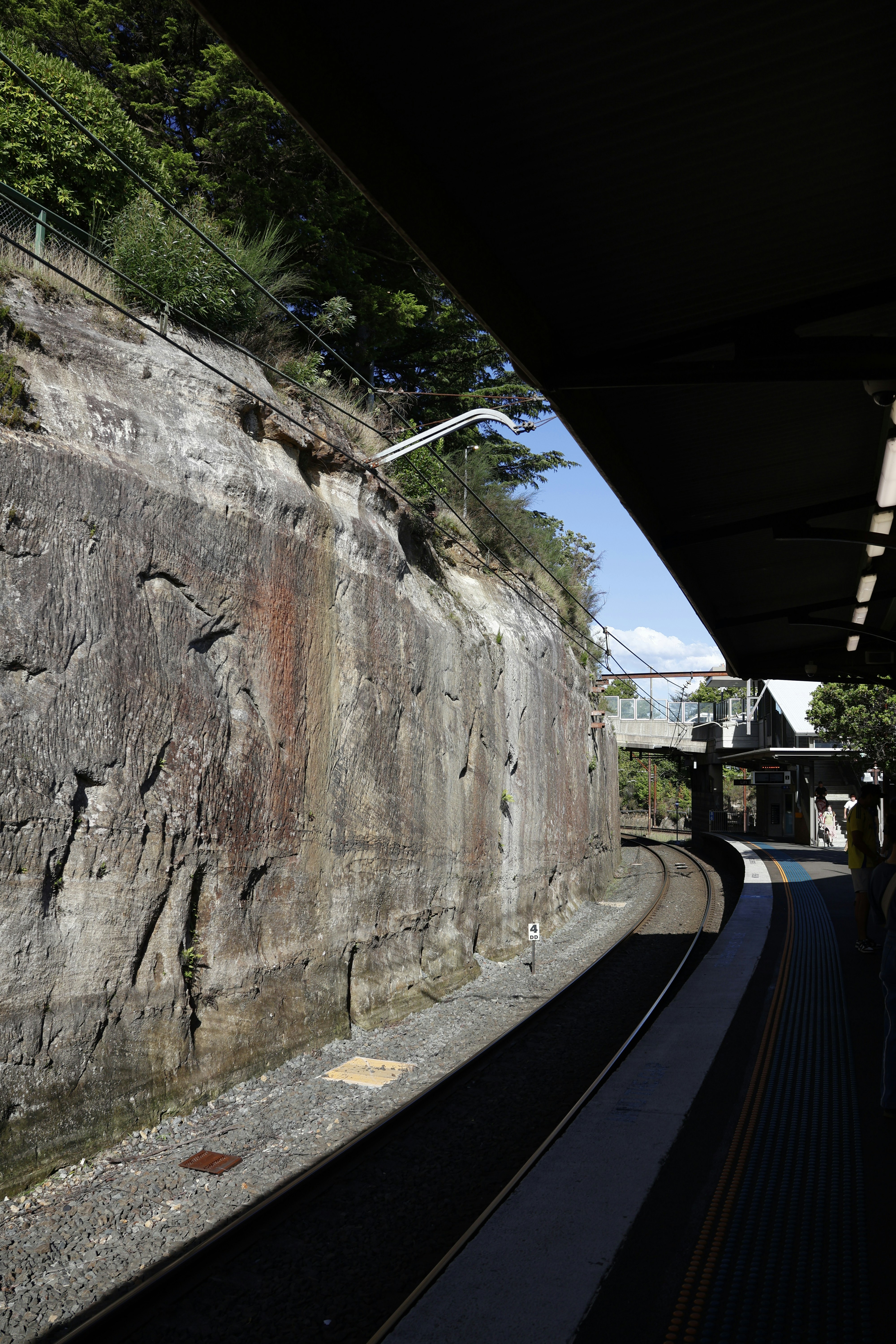 Train tracks alongside a rocky cliff face at a station. photo – Free ...