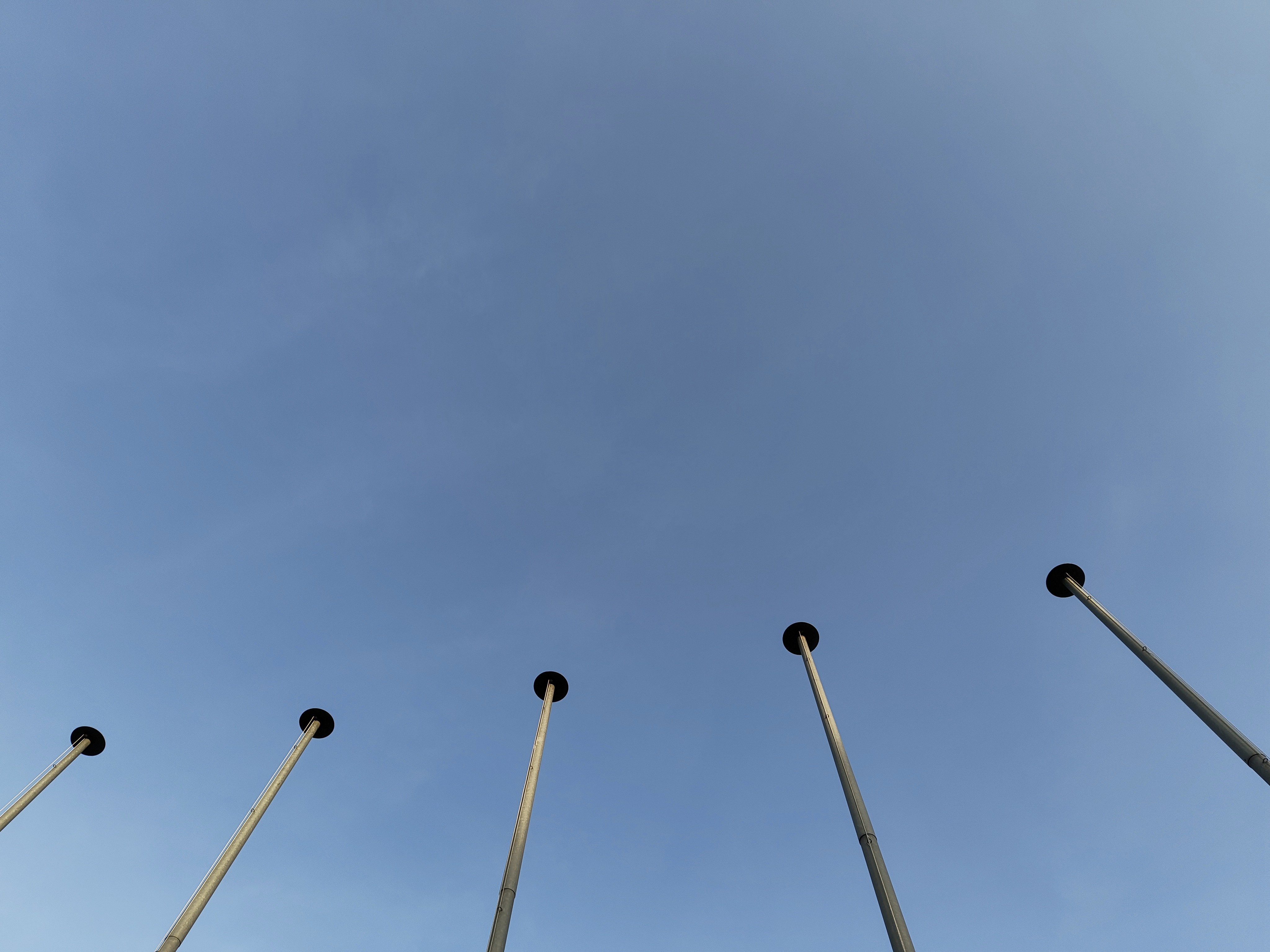 Five poles reaching towards a clear blue sky.
