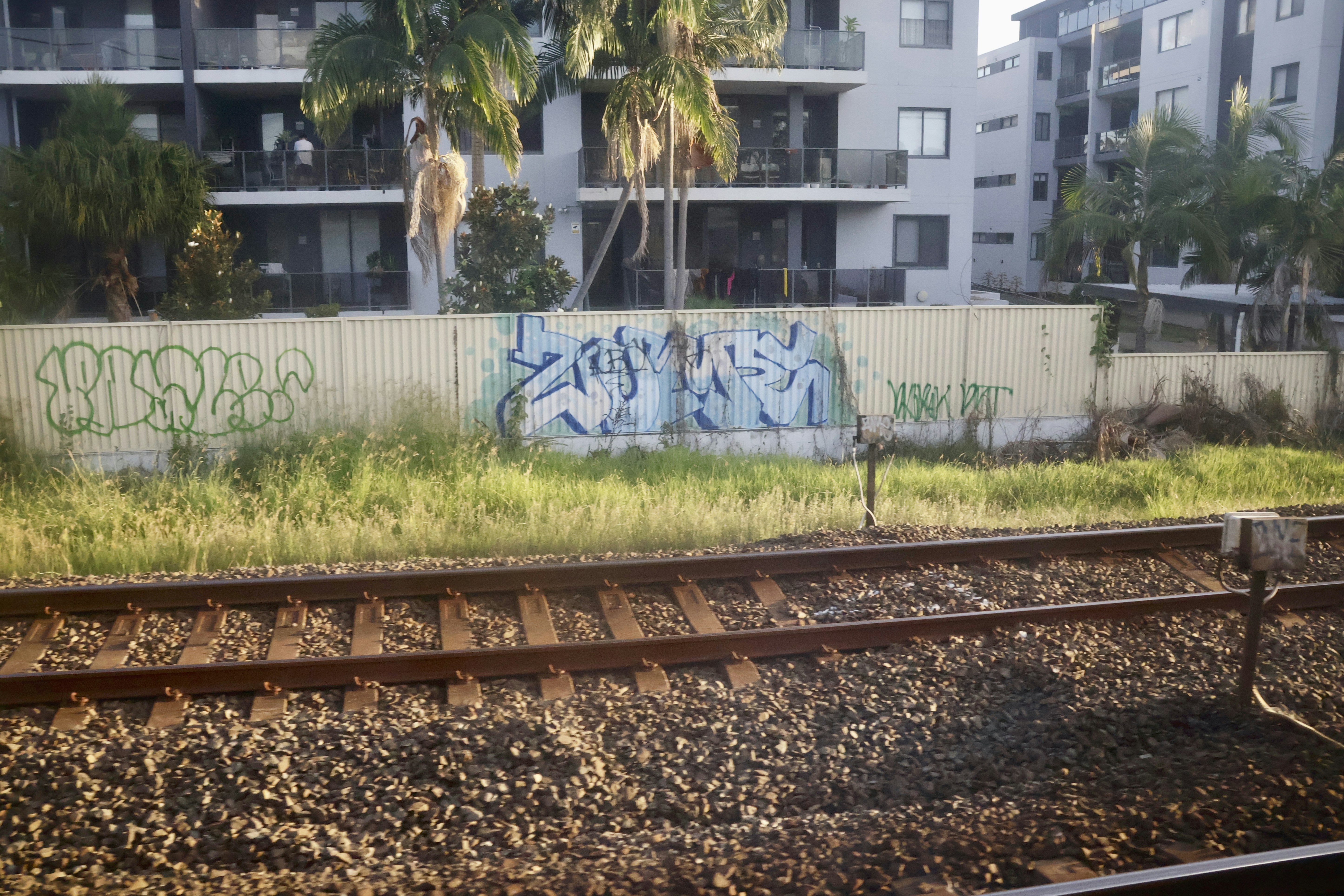 Graffitied industrial wall beyond rusted tracks