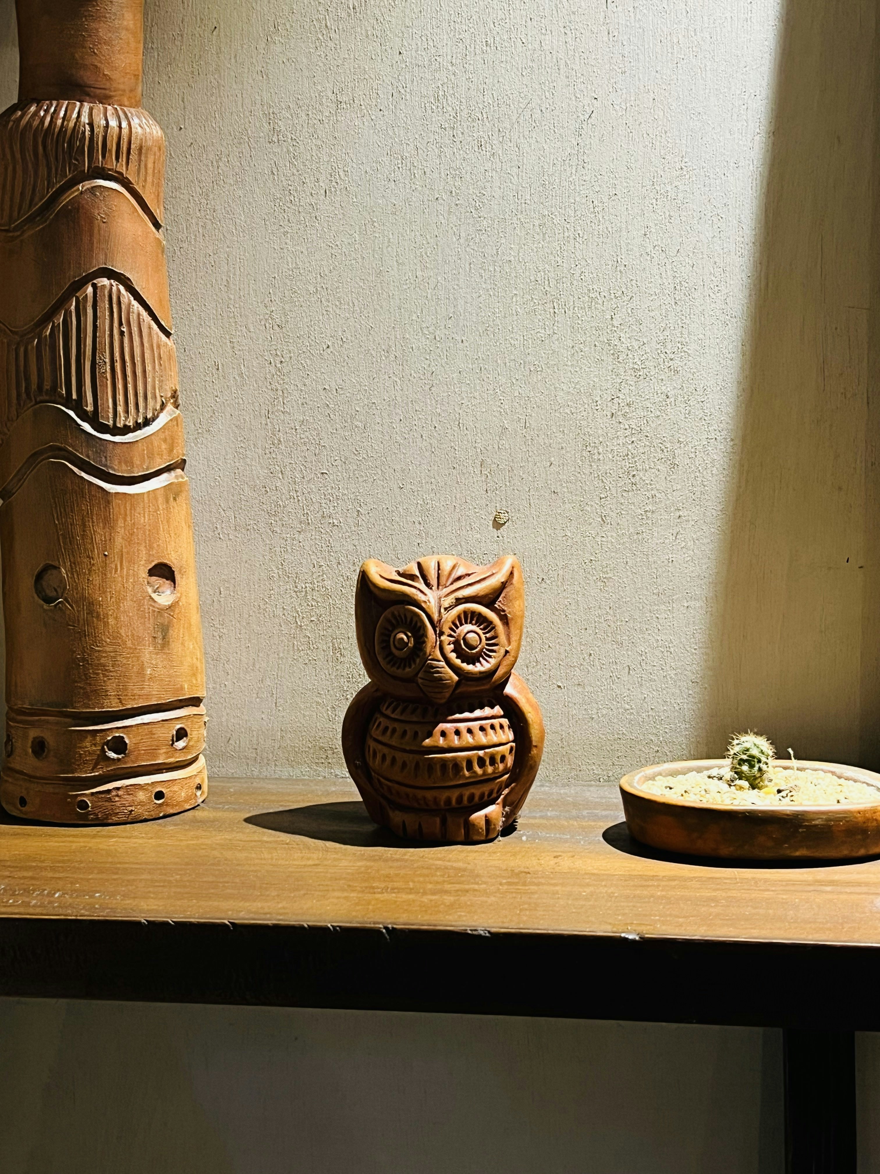 Wooden owl figurine on a shelf with decor.
