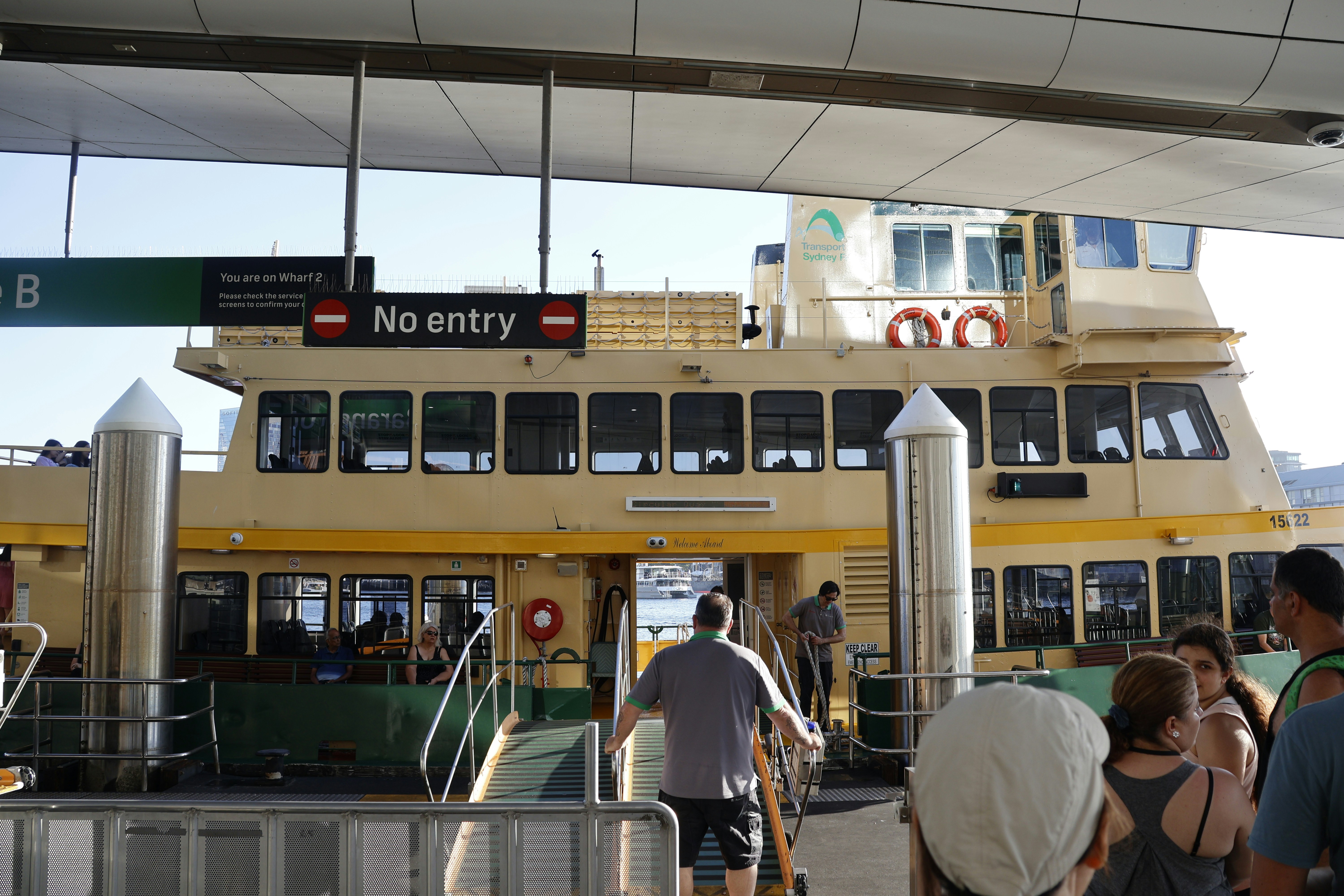 Passengers Await Boarding A Yellow Ferry at a Busy Terminal