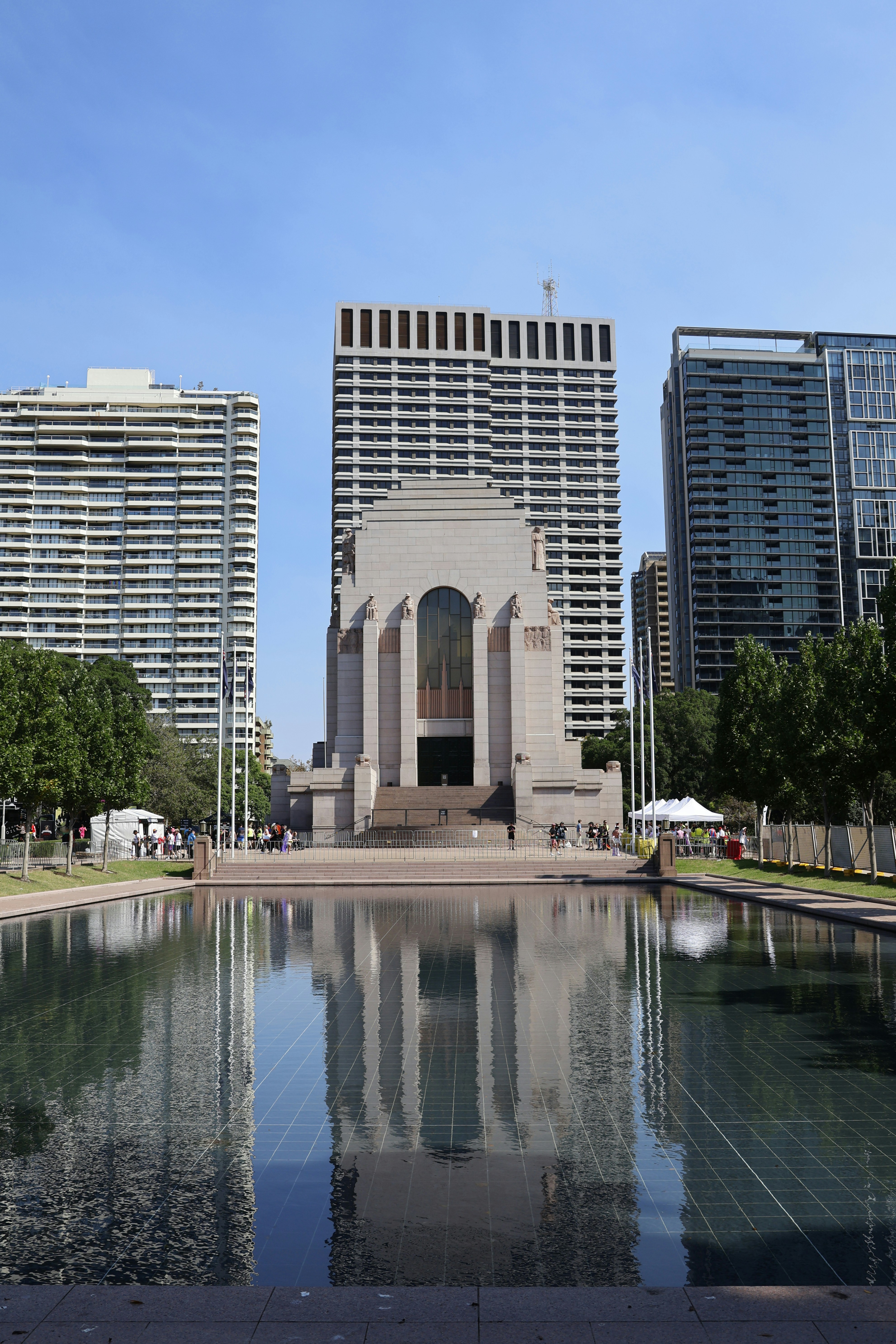 Monument reflected in water with modern buildings behindYou Le