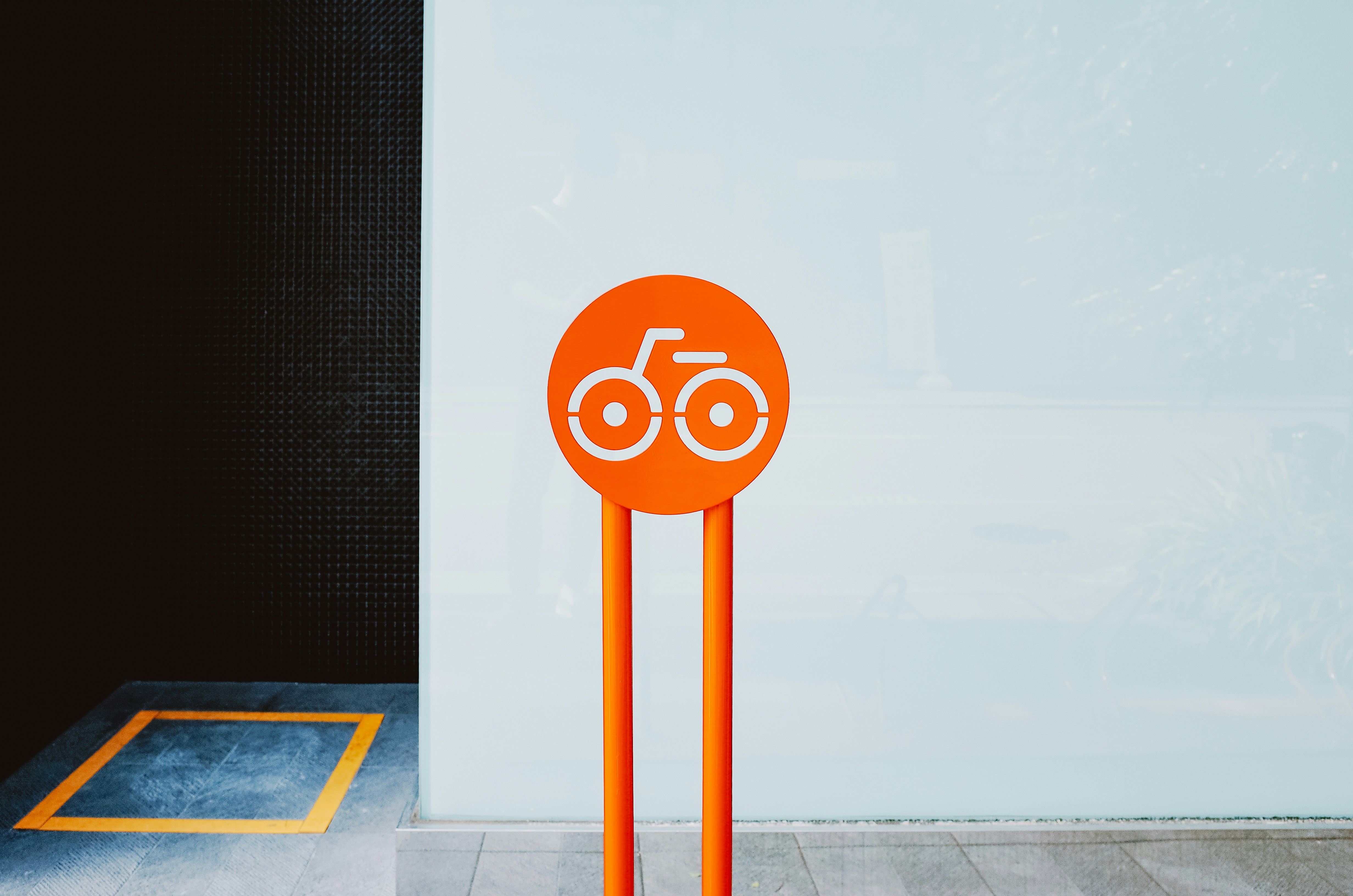 Orange bike icon on bright storefront with yellow-tiled floor edge