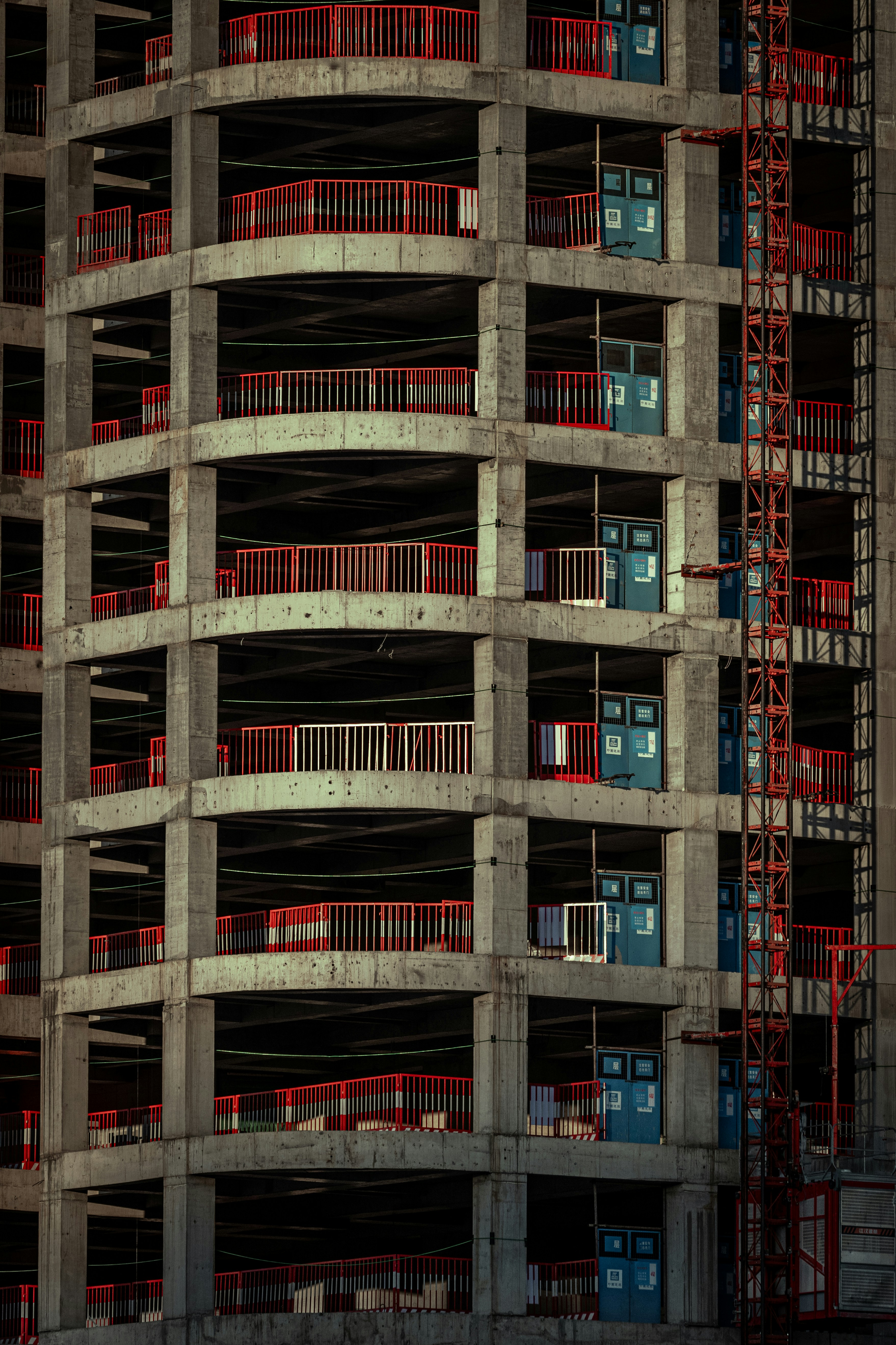 Vertical Skeleton: Red‑Rail Balconies on a Concrete Atrium