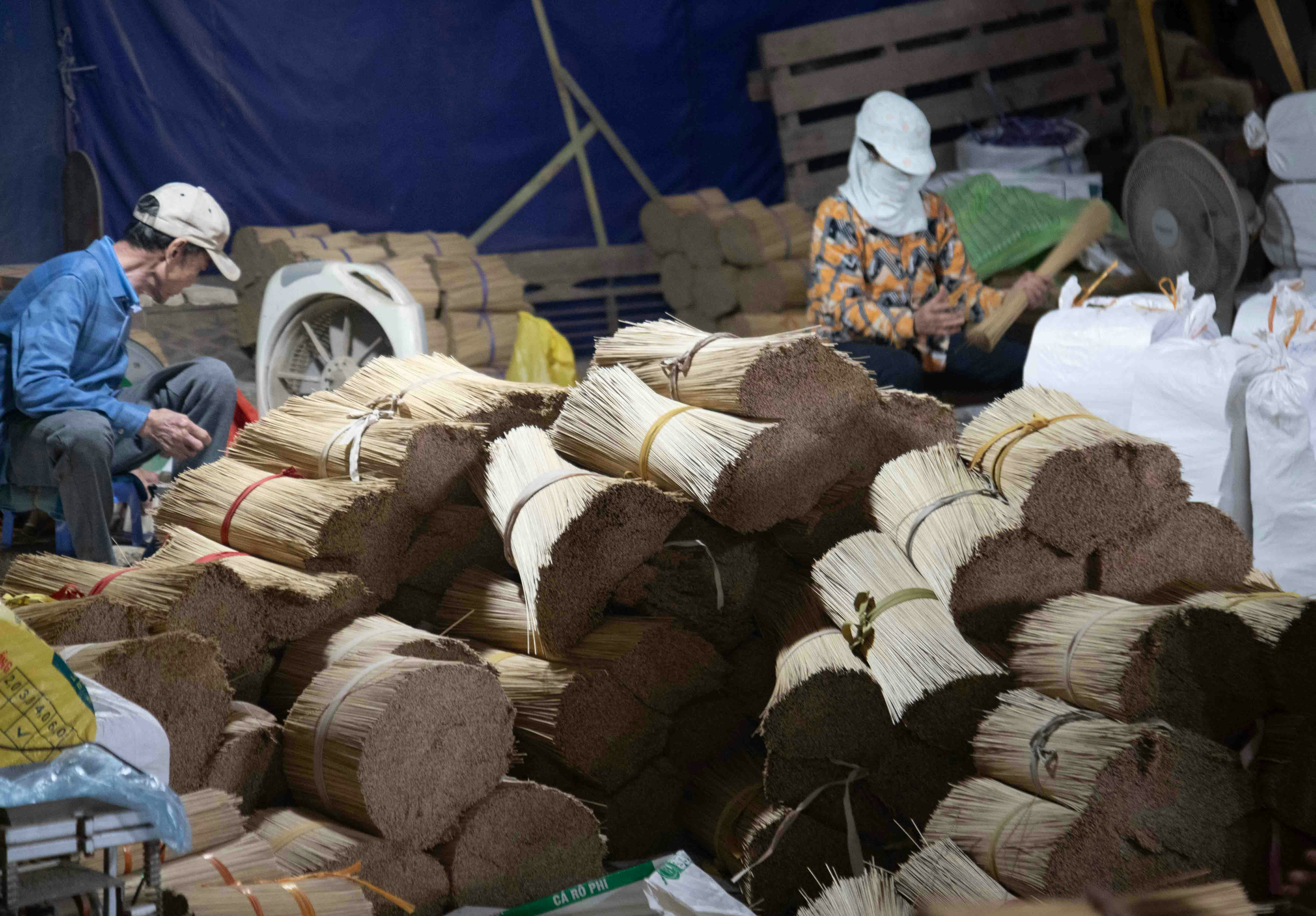 Workers sorting bundles of dried reeds in a warehouse