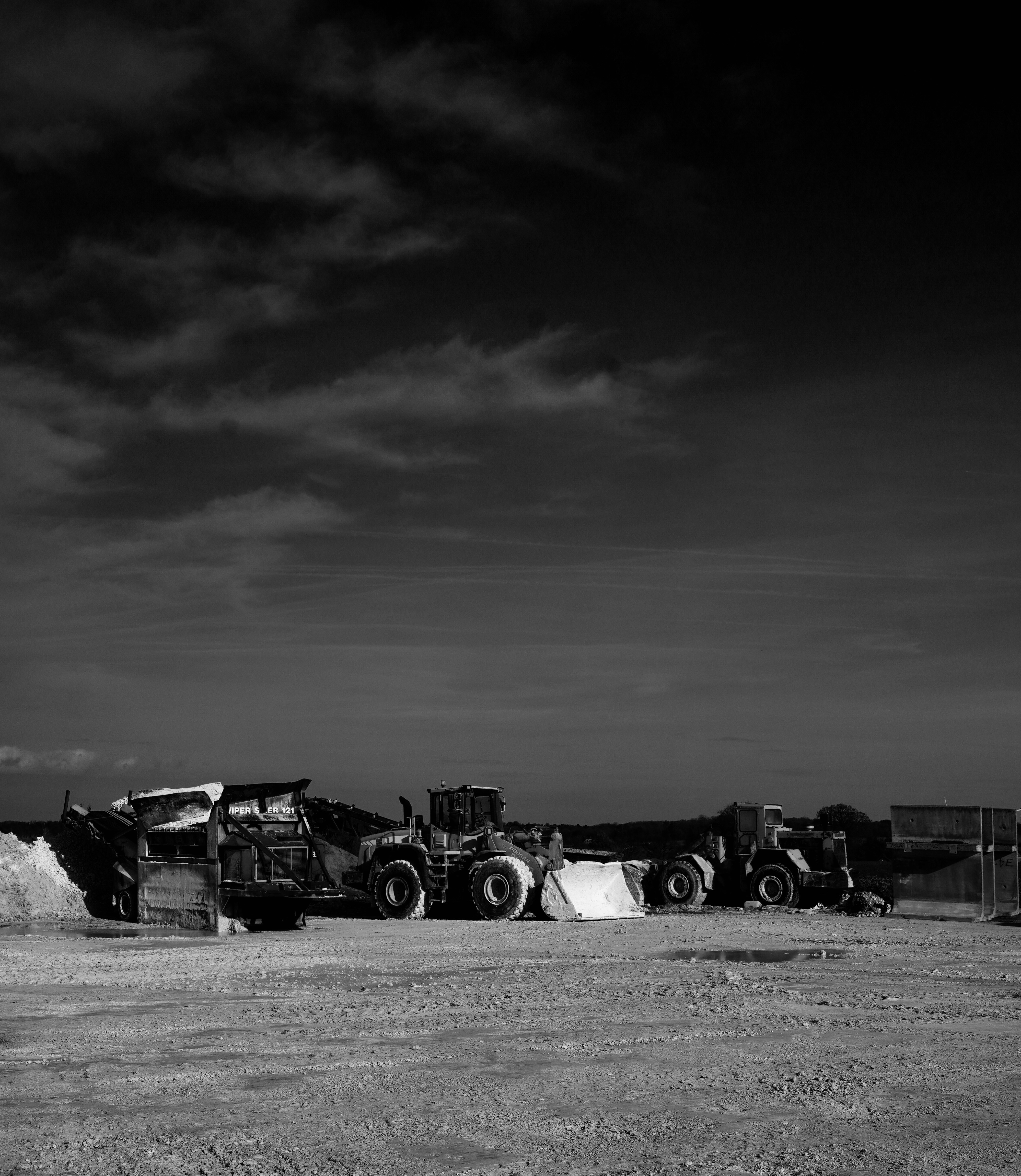 Earthbound Machinery: Dump Trucks Rest Against a Quiet Construction Site