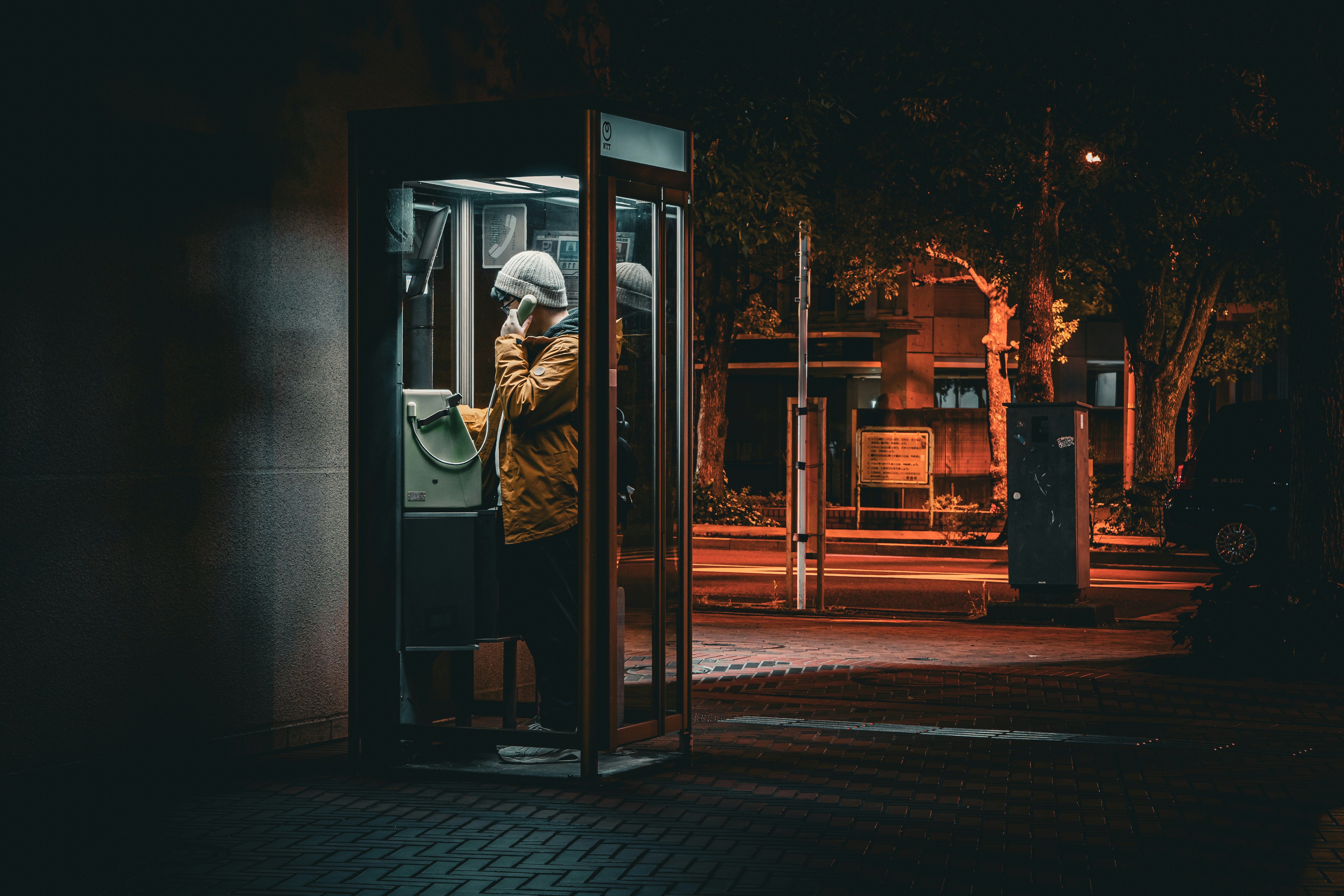 Nighttime Phone Booth: A Lone Caller Under Streetlight